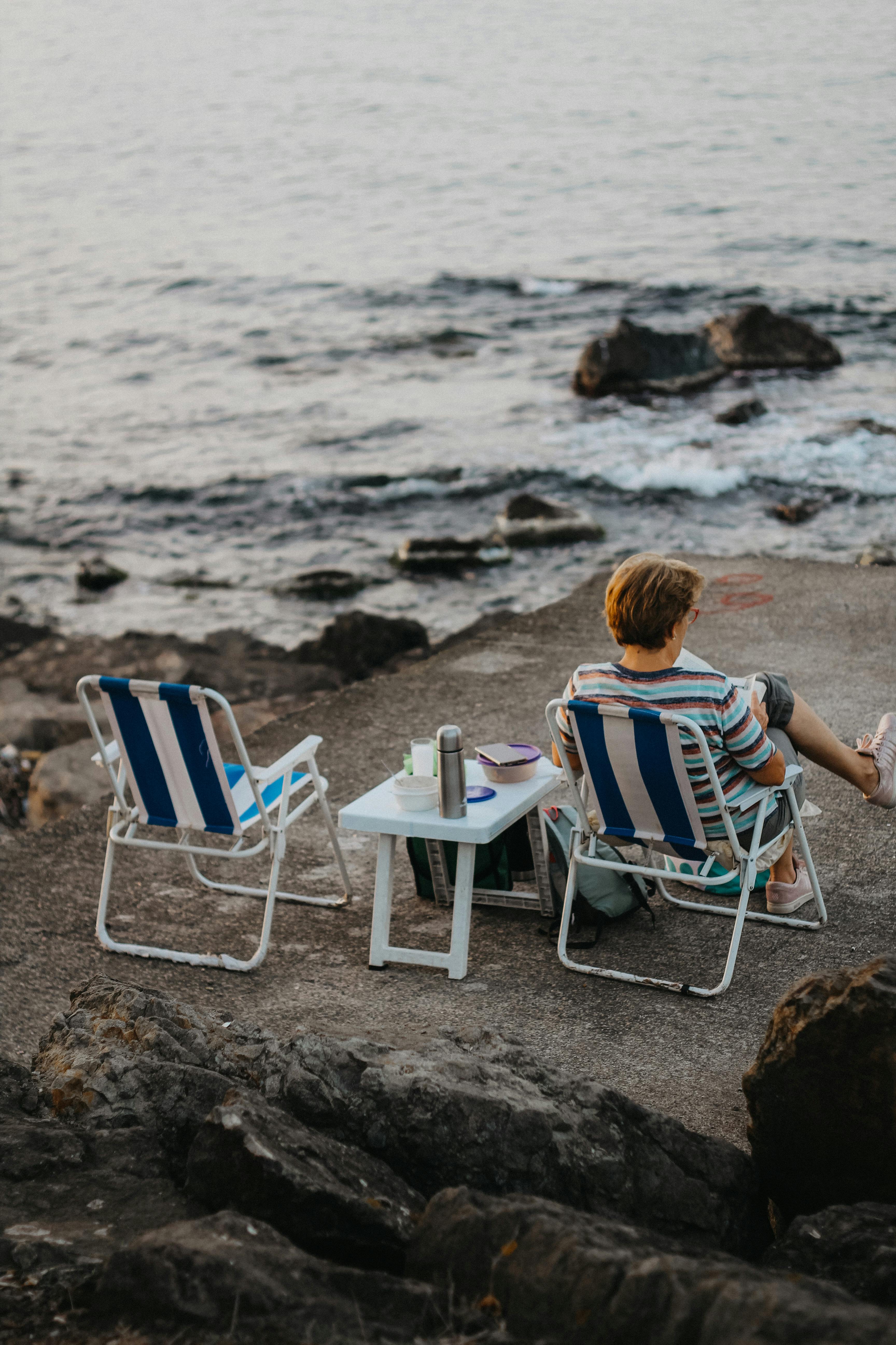 Man Sitting on Chairs on Sea Shore · Free Stock Photo