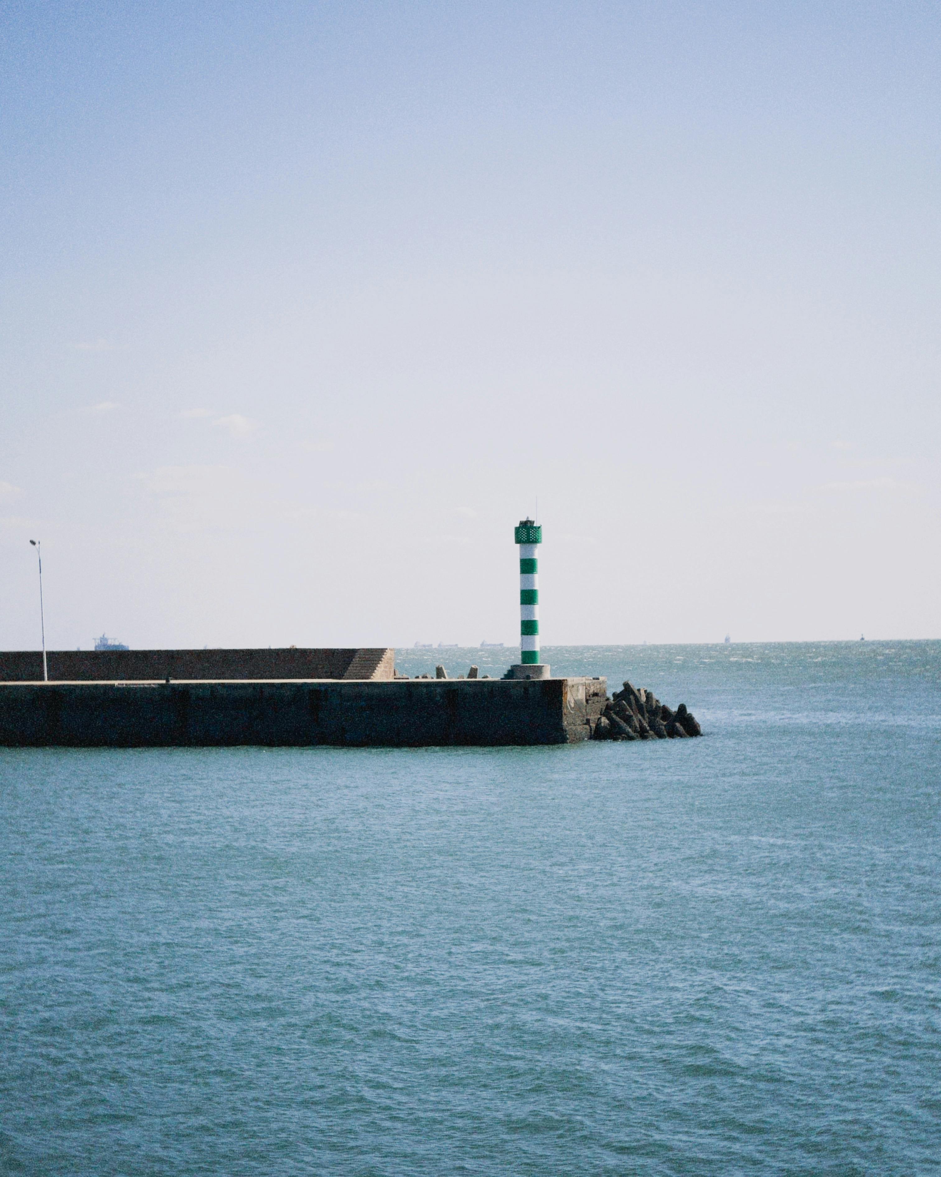 Green and White Lighthouse on a Concrete Dock · Free Stock Photo