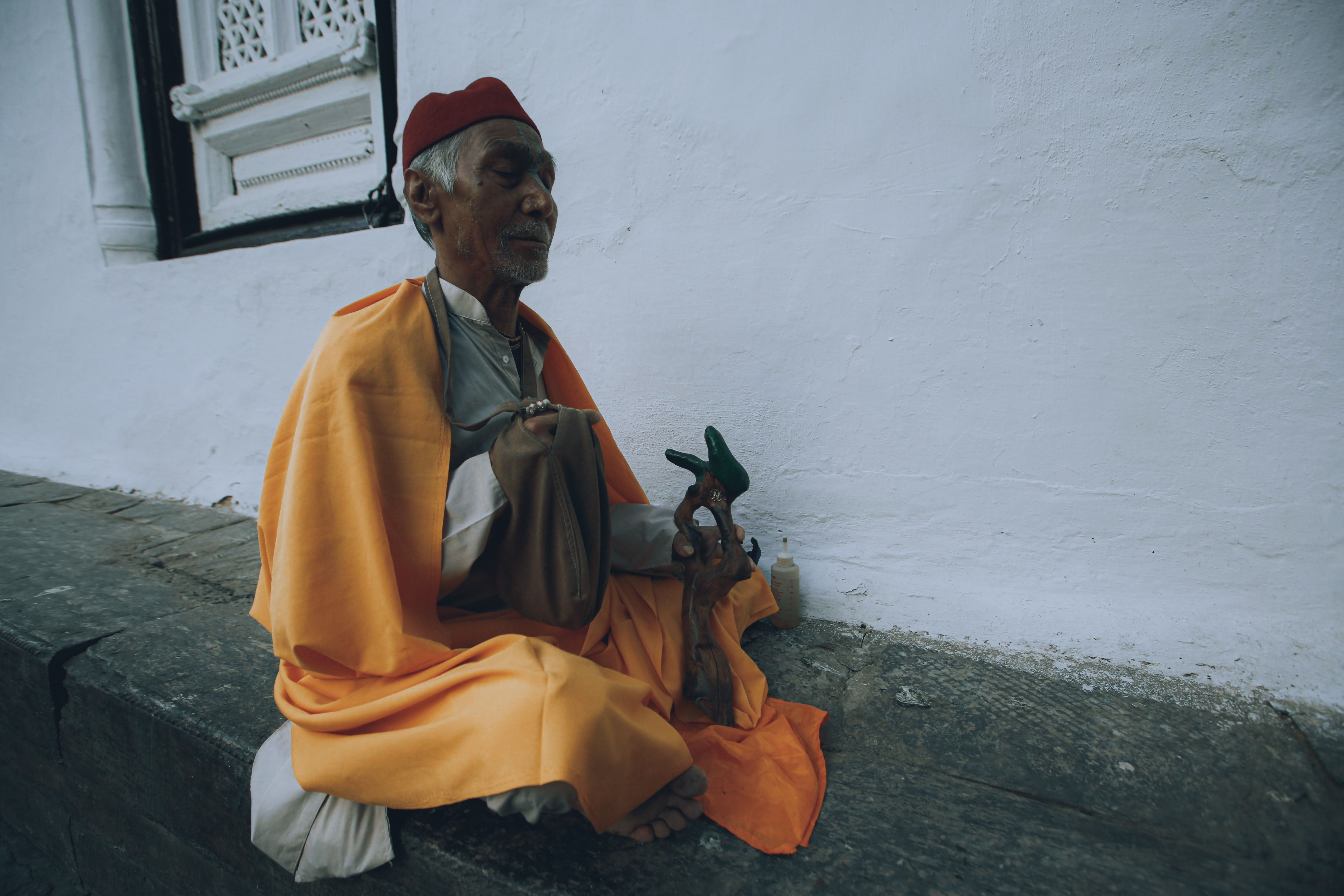 Monk Sitting on Curbside Praying · Free Stock Photo