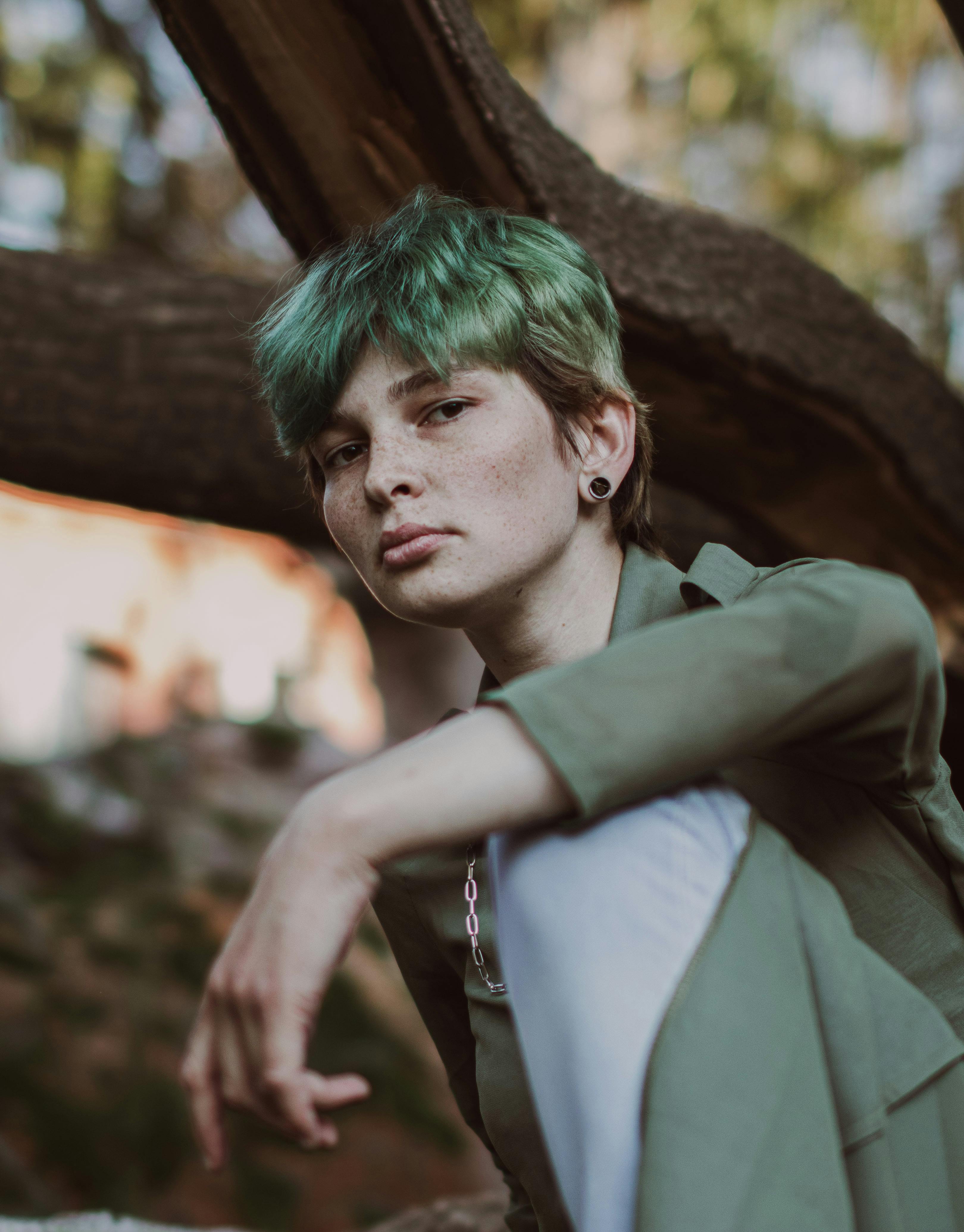 Person in Green Jacket Sitting Near the Tree Trunk · Free Stock Photo