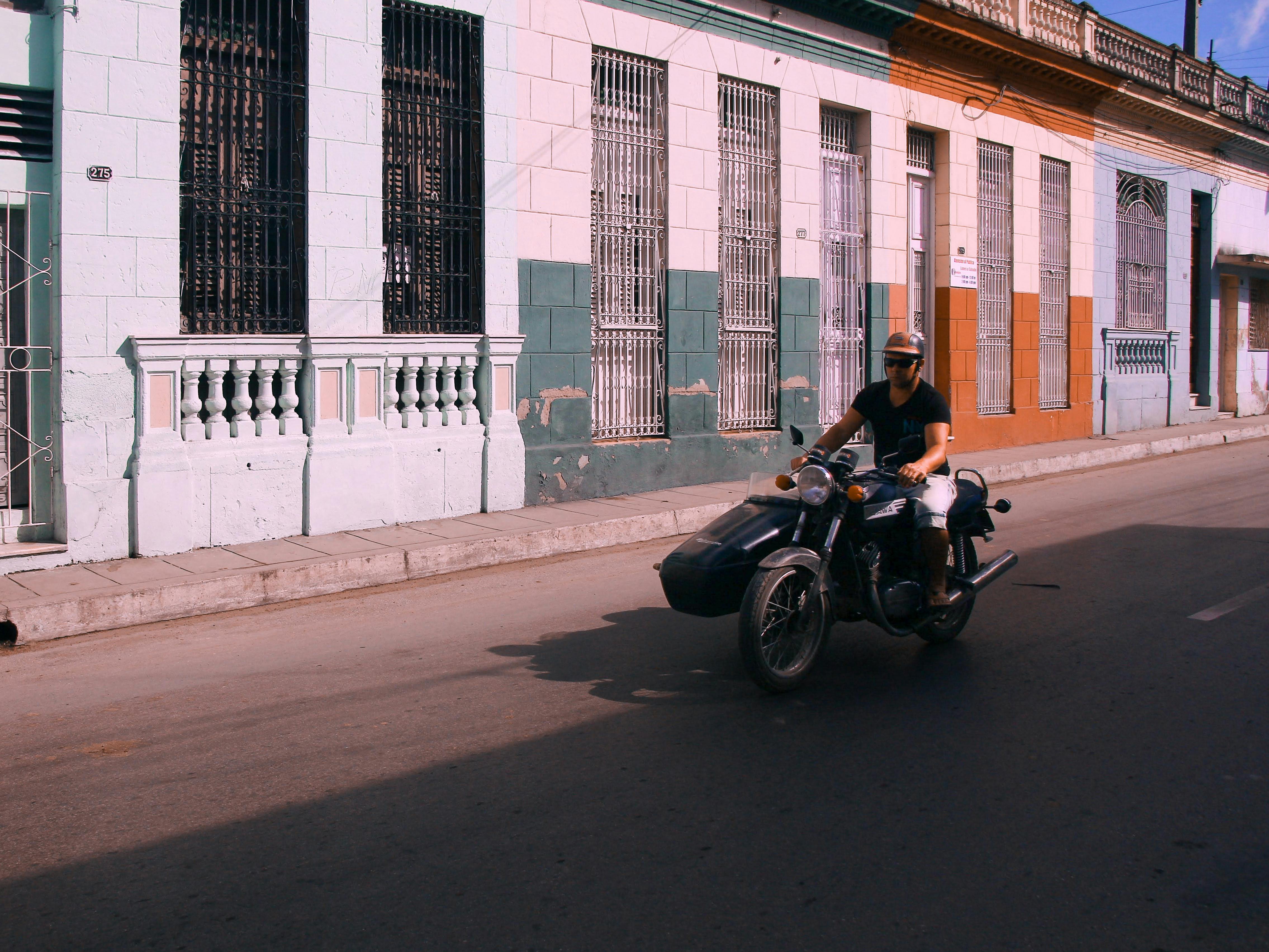 Building Facade with Window Bars and Man Driving Motorbike on a Road ...