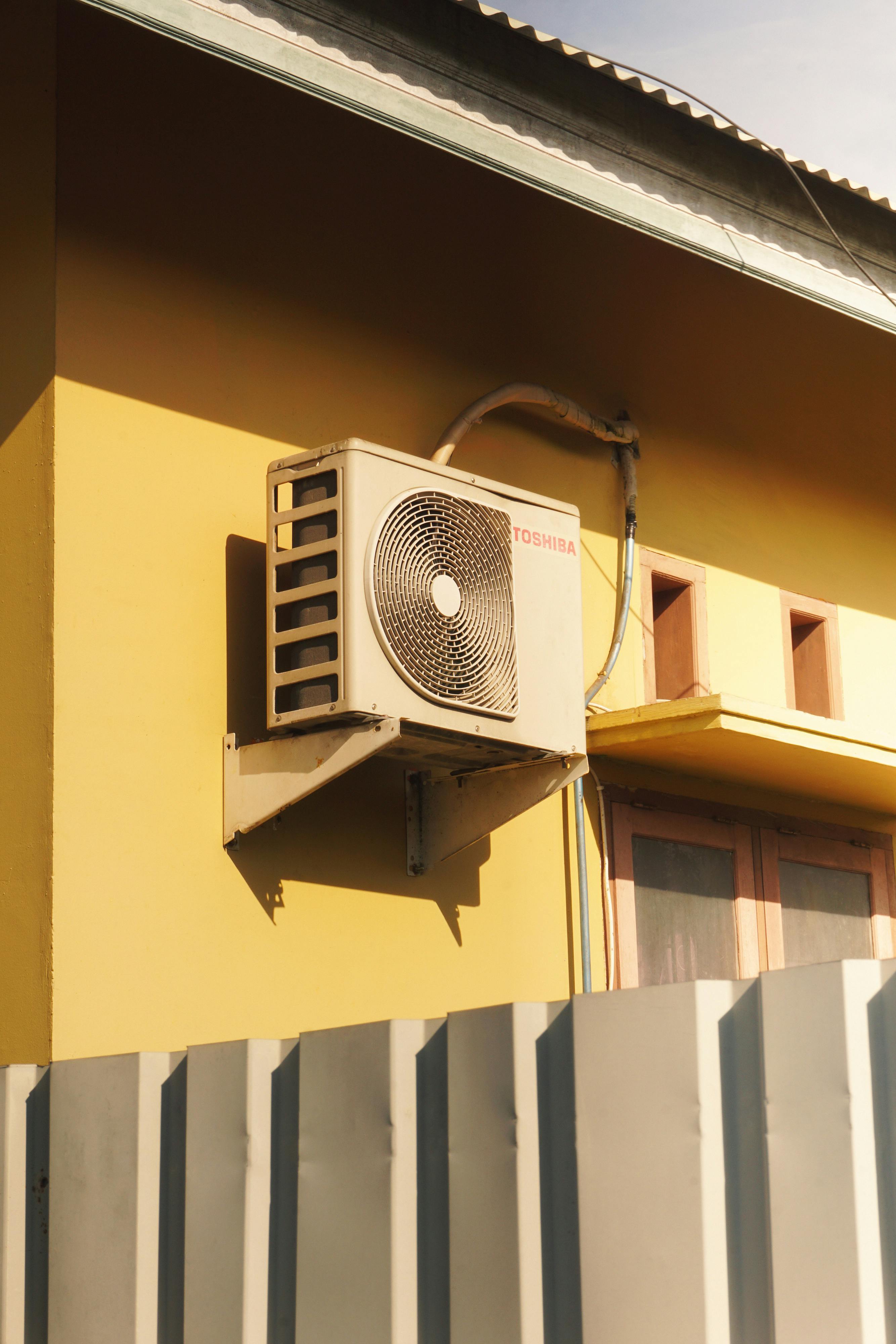 Toshiba Outdoor Air Conditioner Unit on Yellow Wall · Free Stock Photo