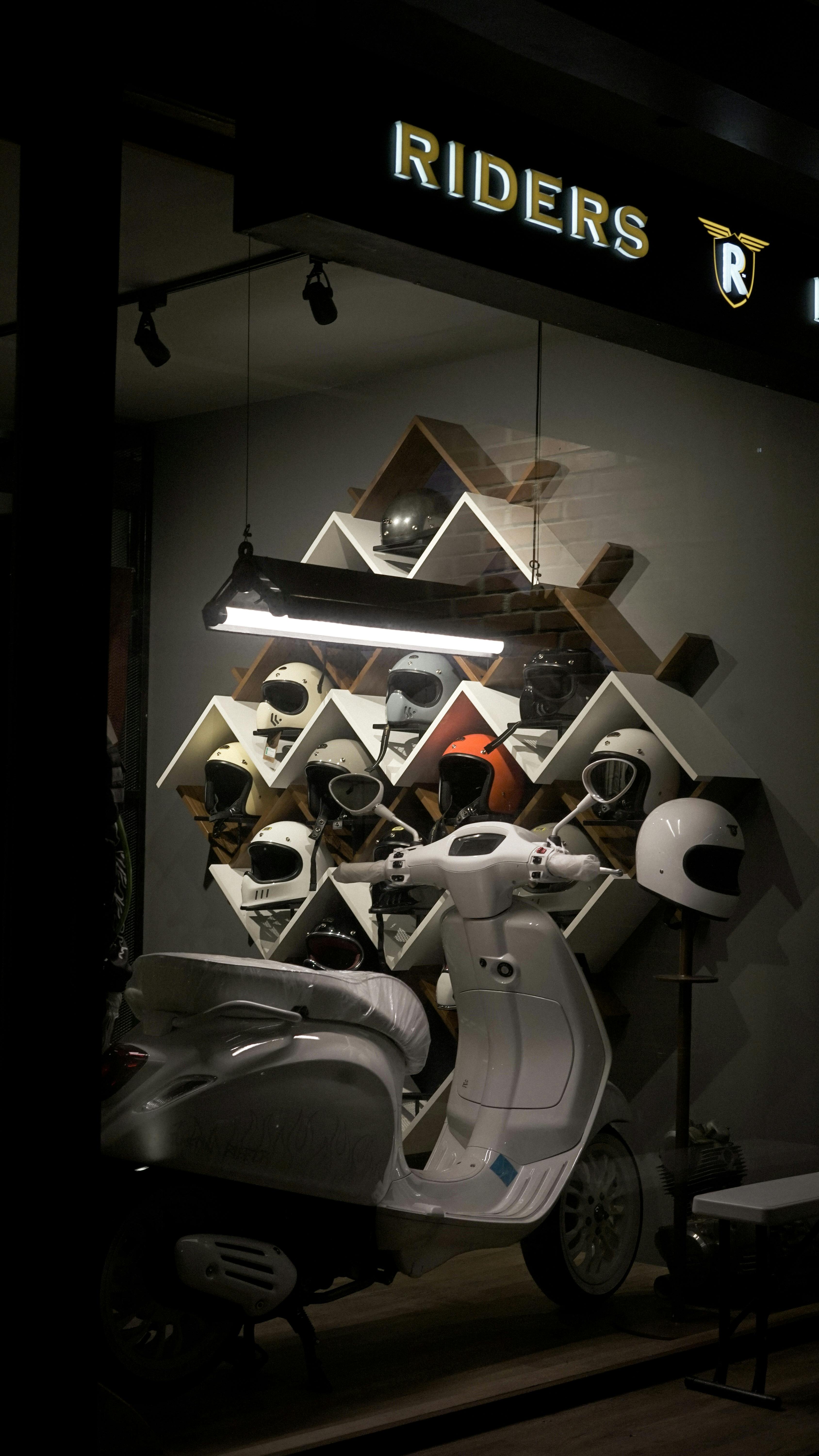 Motorcycle Helmets Displayed on Shelf Next to White Scooter · Free ...