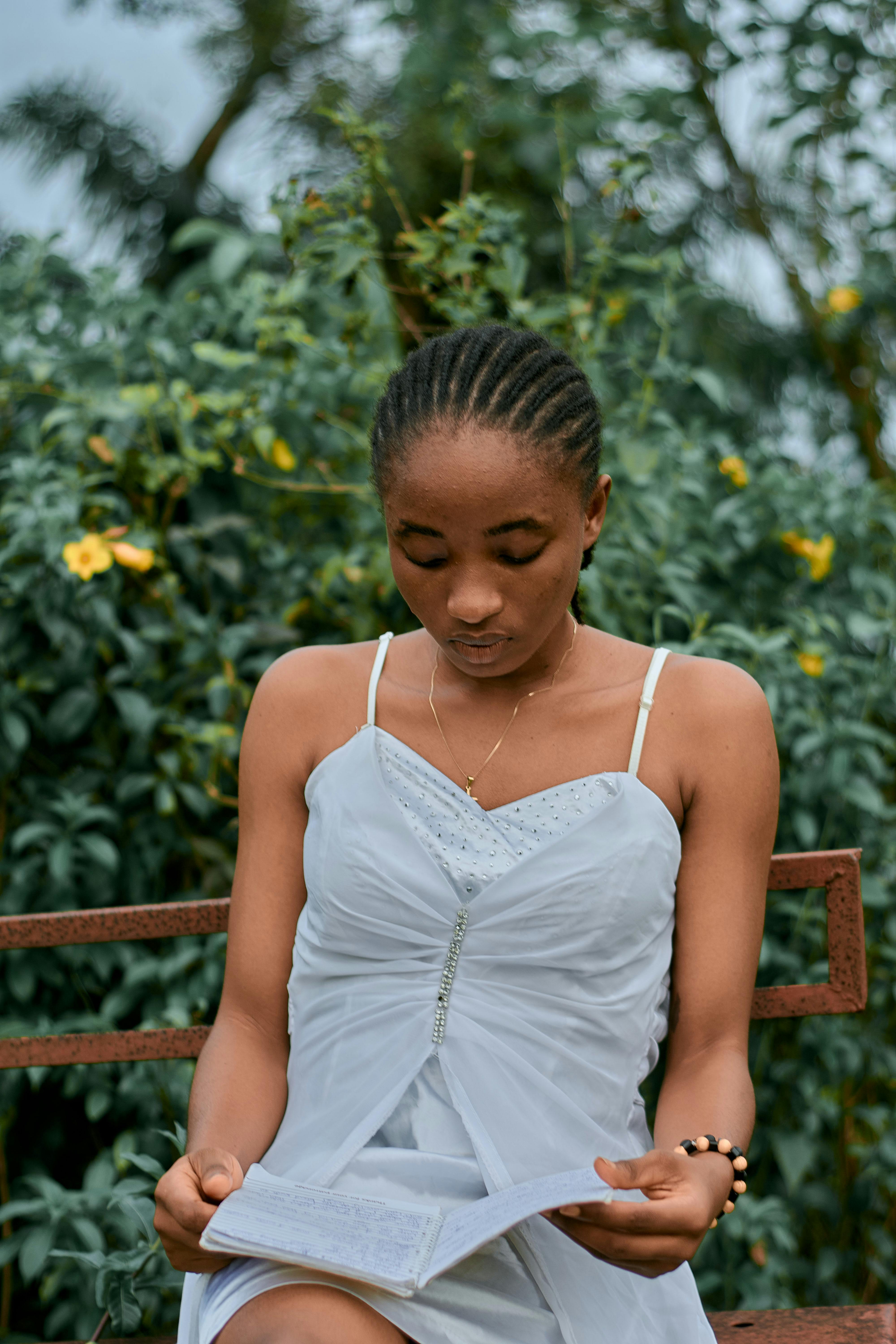 Young Woman in a White Blouse Sitting on a Bench and Reading a Notebook ...
