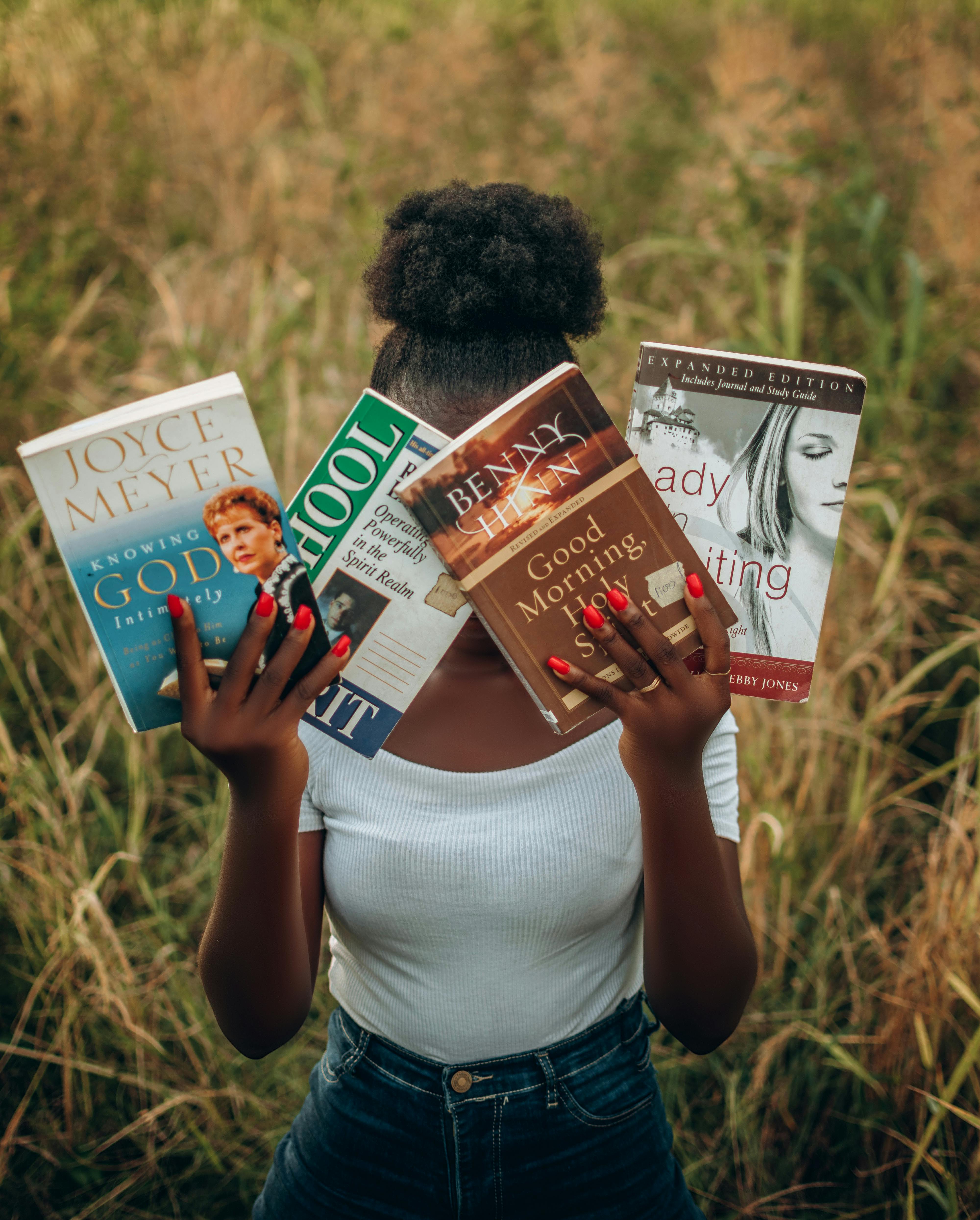 Woman in a Grass Field Holding Books · Free Stock Photo