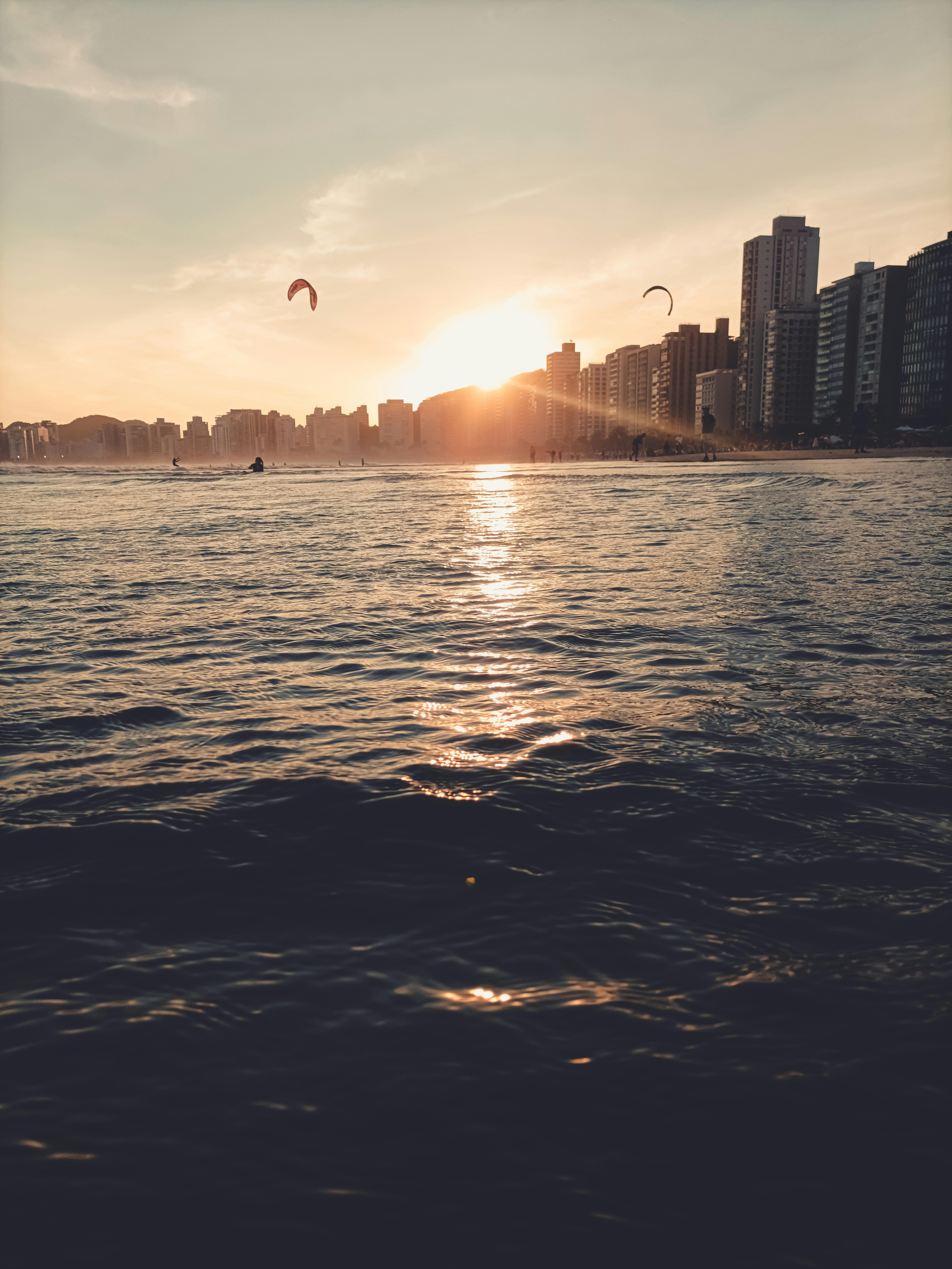 Sunset above Sea near Coastal City · Free Stock Photo