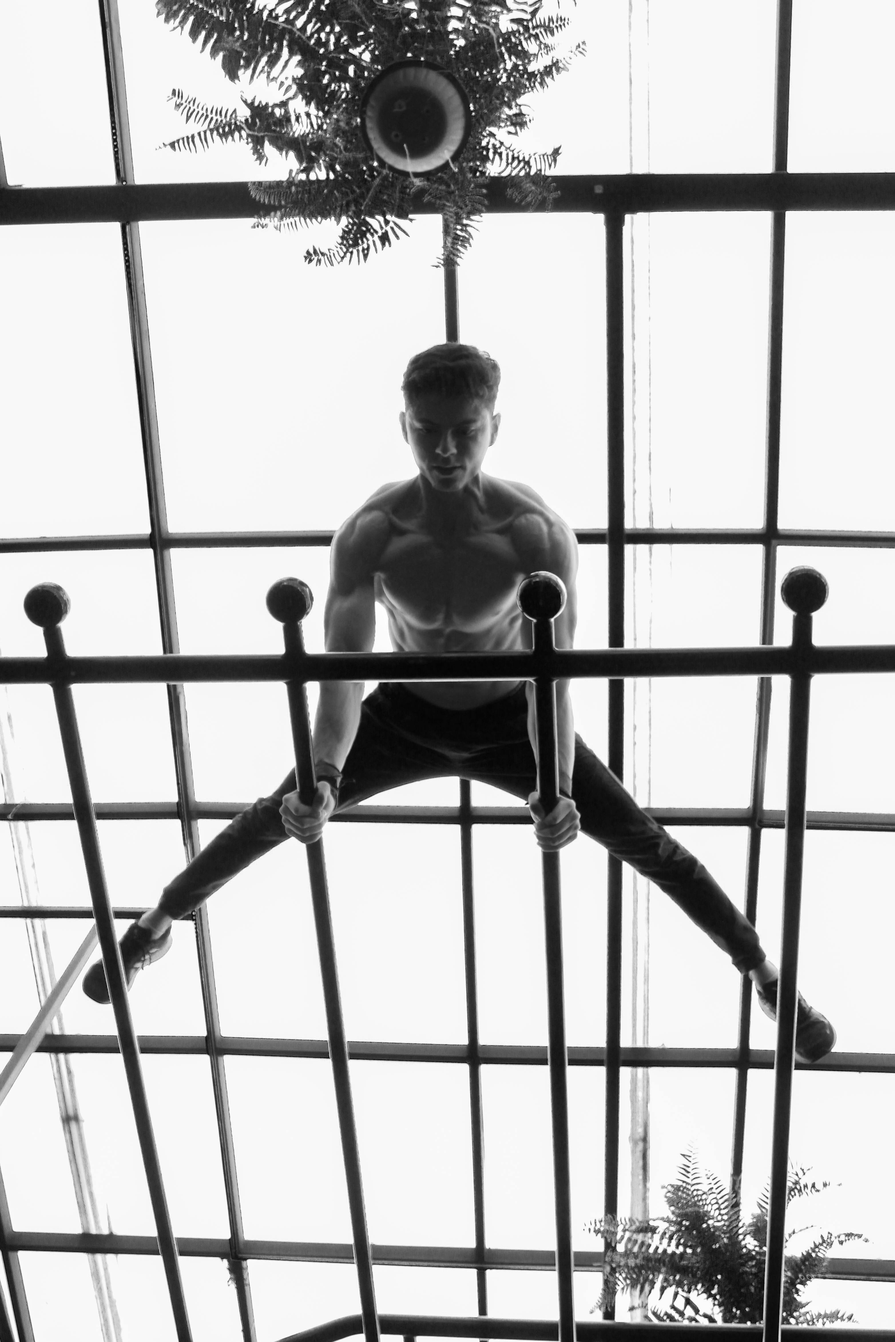 Flexible man in skirt with leg on back of chair · Free Stock Photo