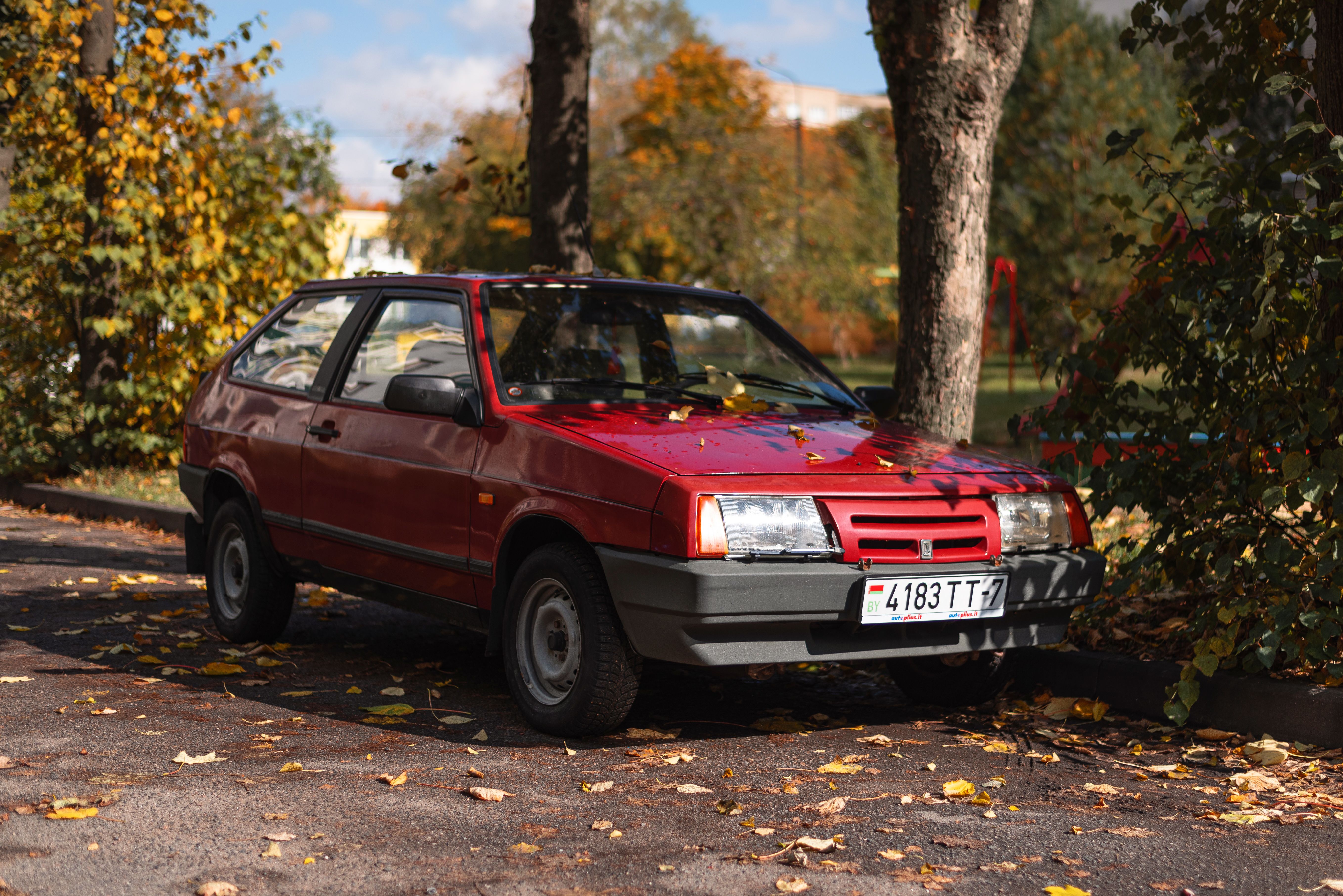 A Red Car Parked Near a Tree · Free Stock Photo