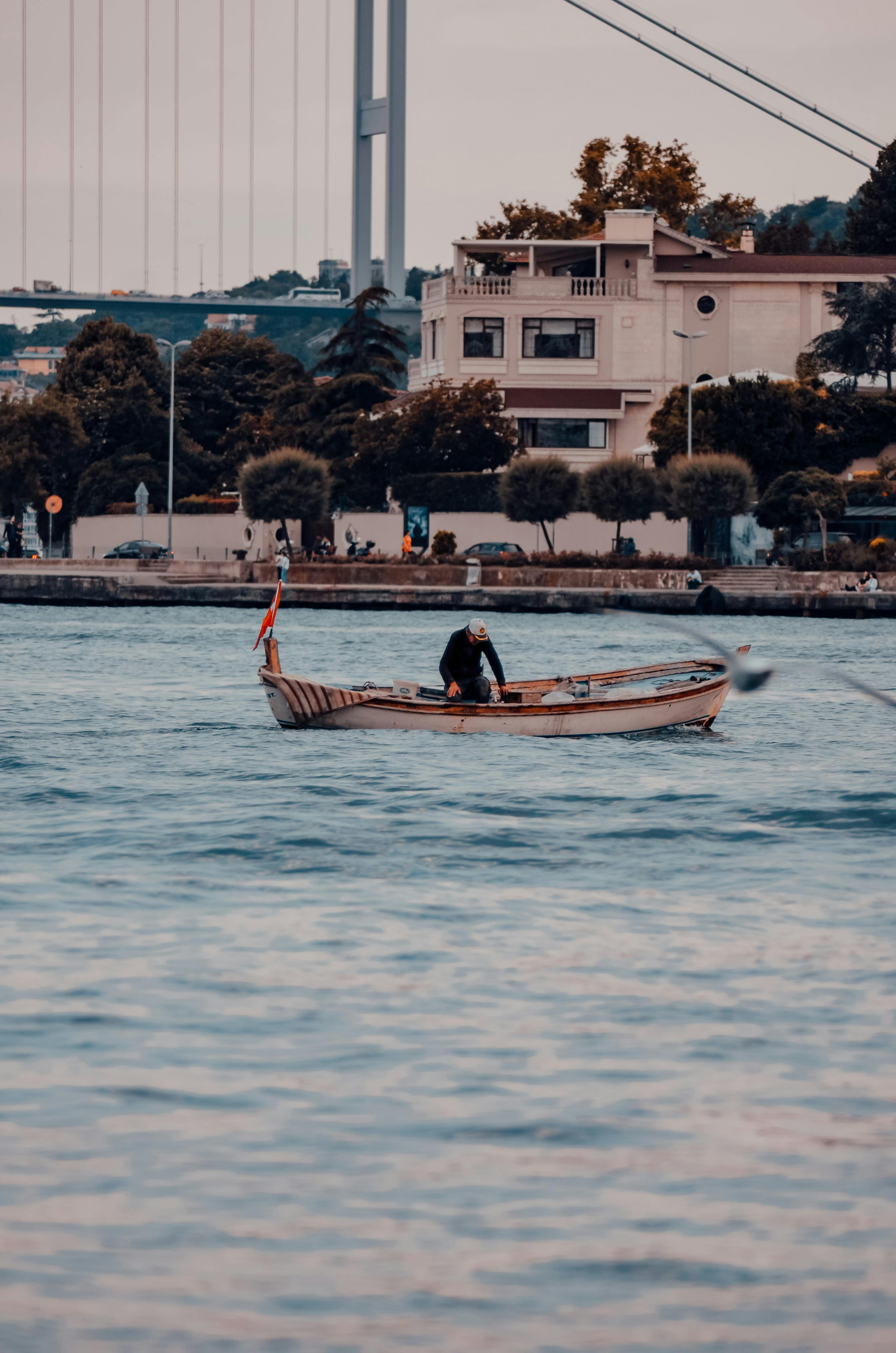 Man Riding a Wooden Boat on the Bay · Free Stock Photo