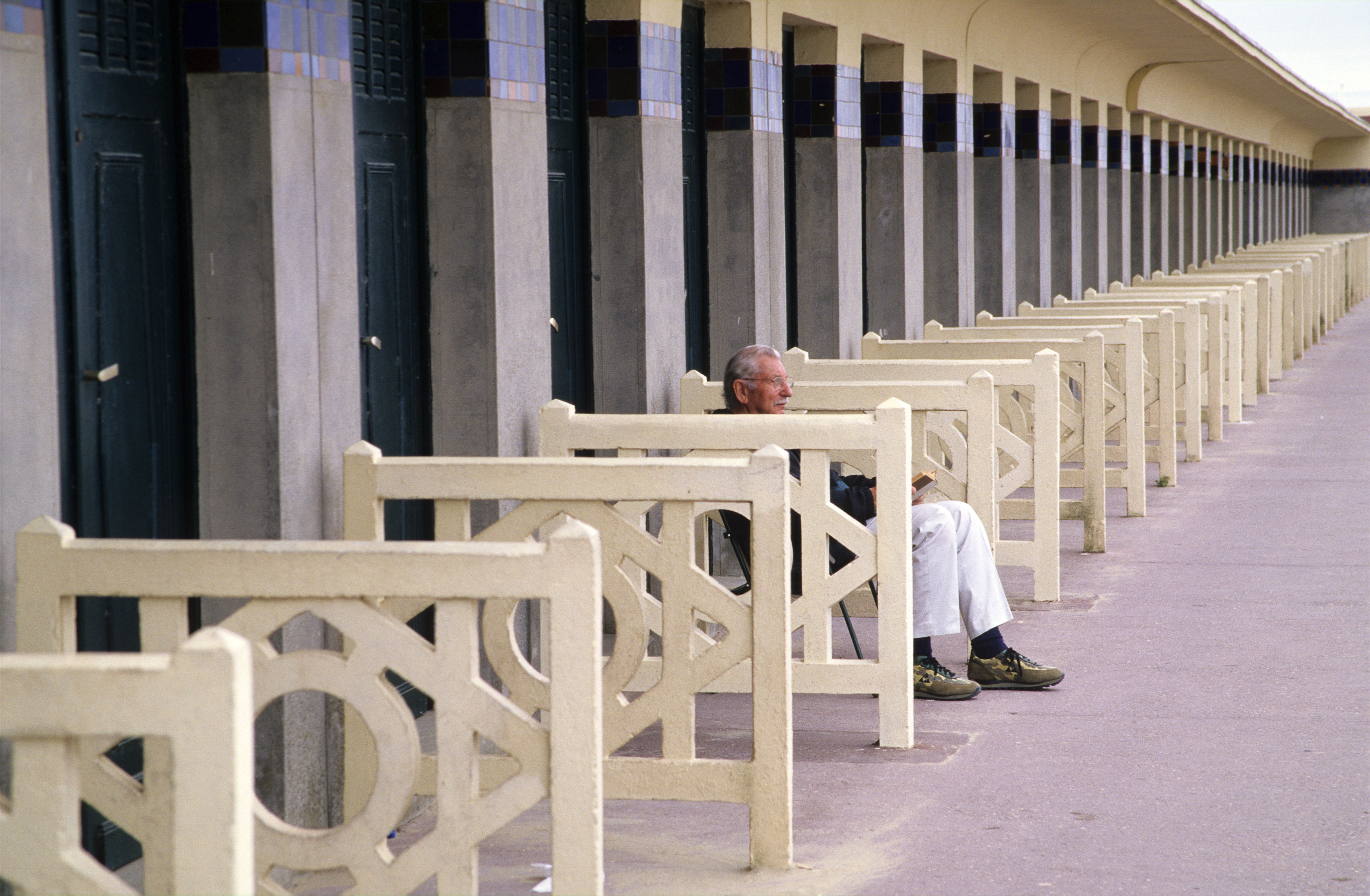 Man Sitting by Wall with Doors and Railings · Free Stock Photo