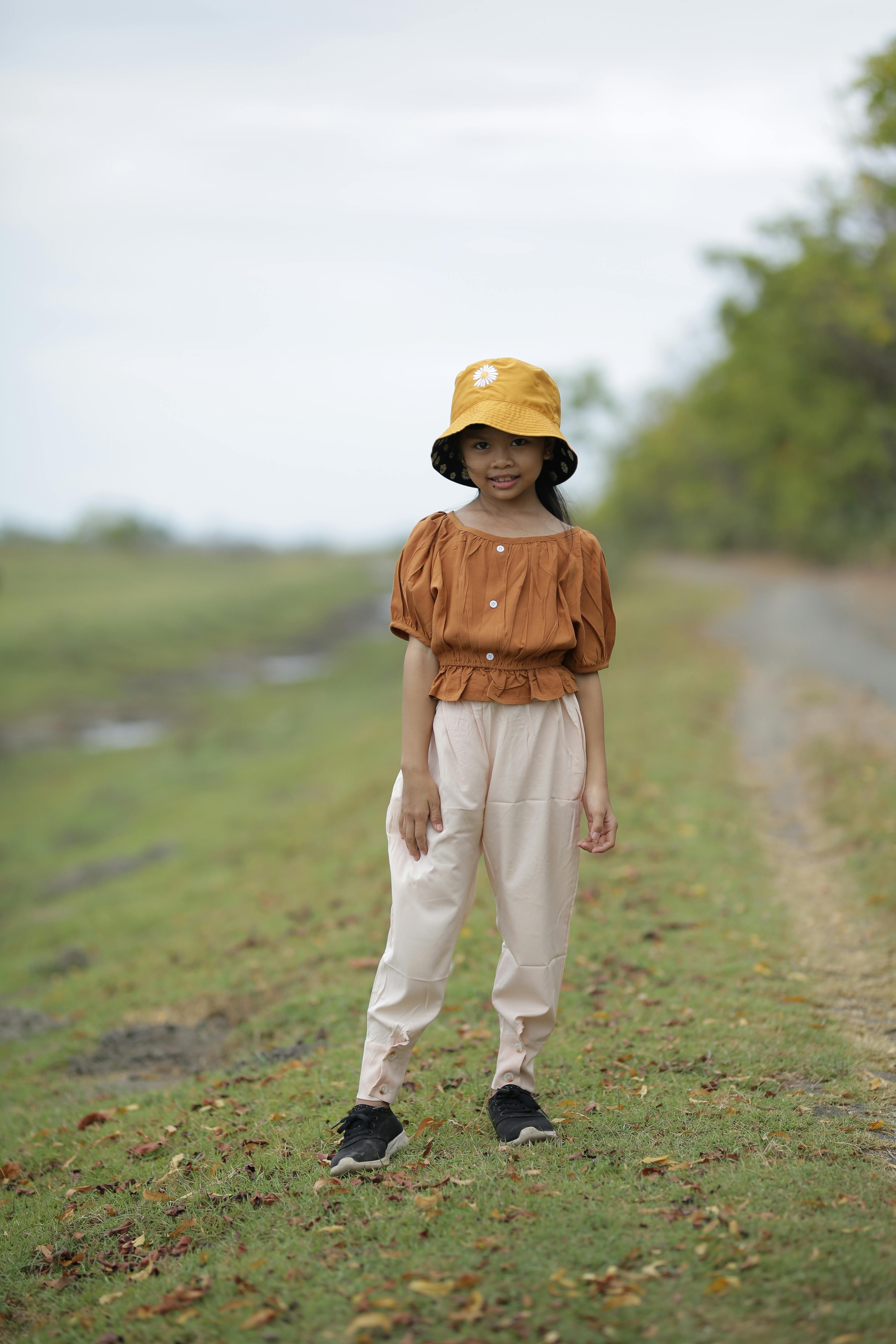 A Girl with a Bucket Hat Standing on the Grass · Free Stock Photo