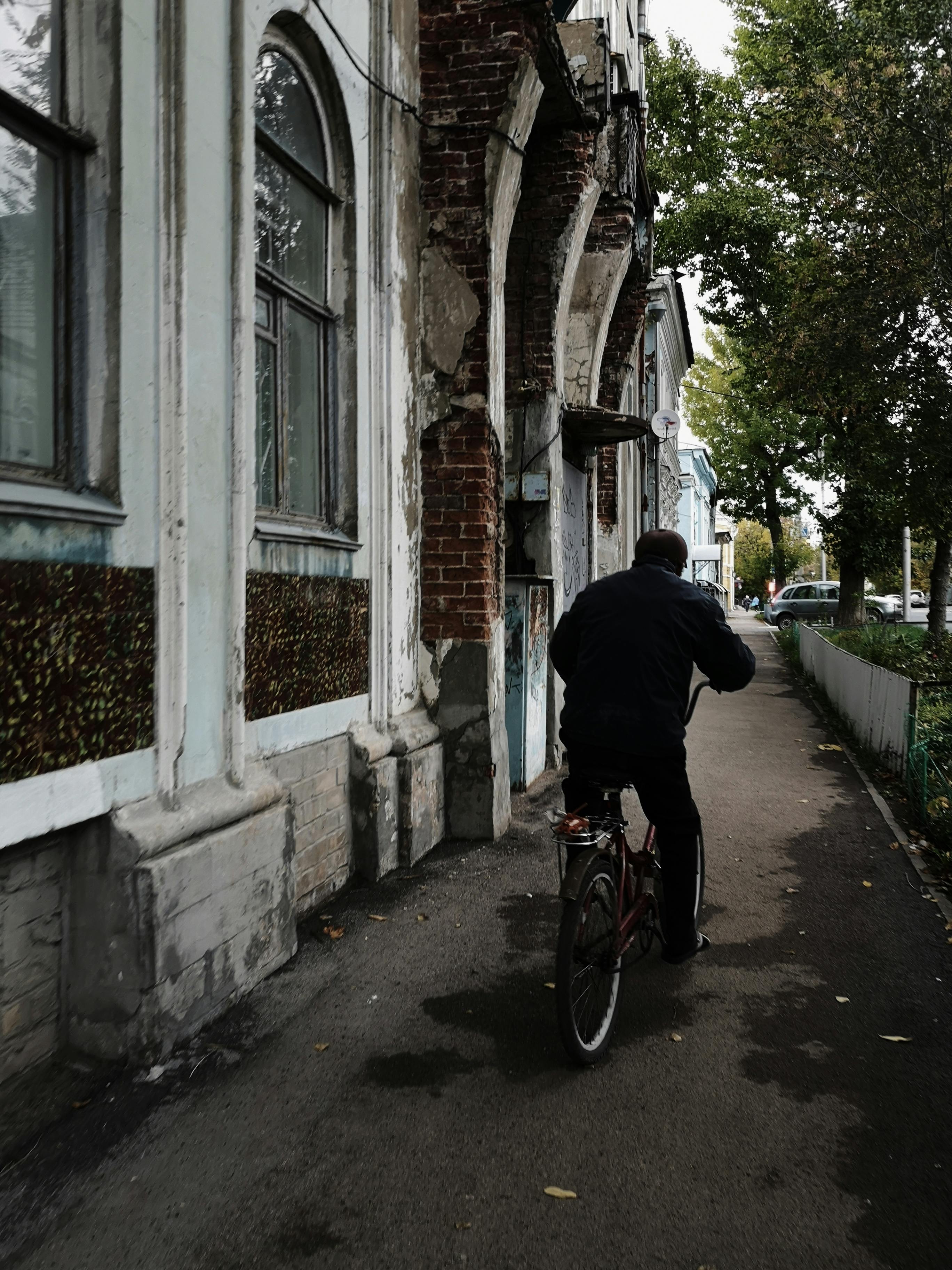 Man in a Coat Riding a Bicycle Down the Street · Free Stock Photo