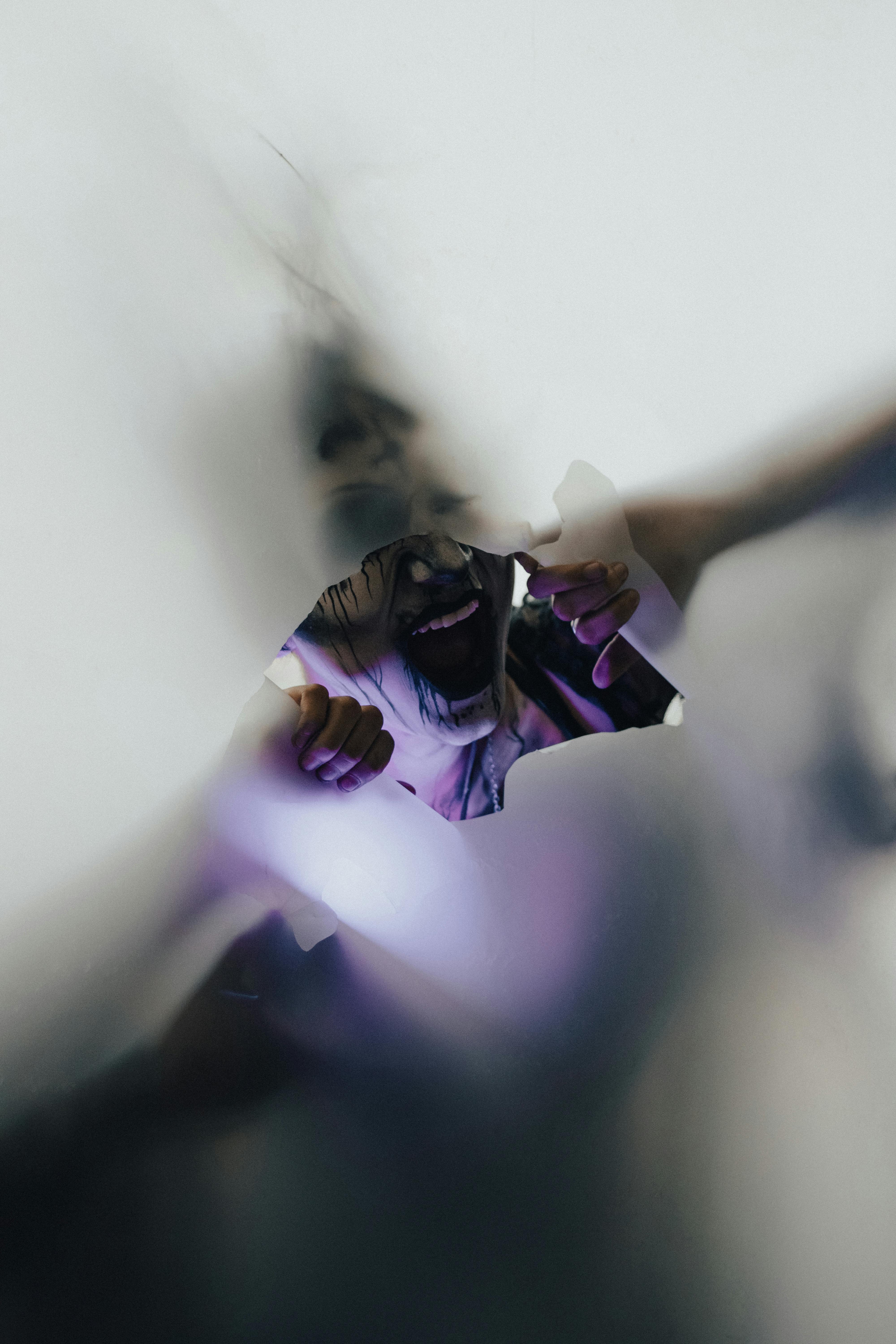 Person in a Scary Halloween Mask Looking through a Ripped Hole in Paper ...
