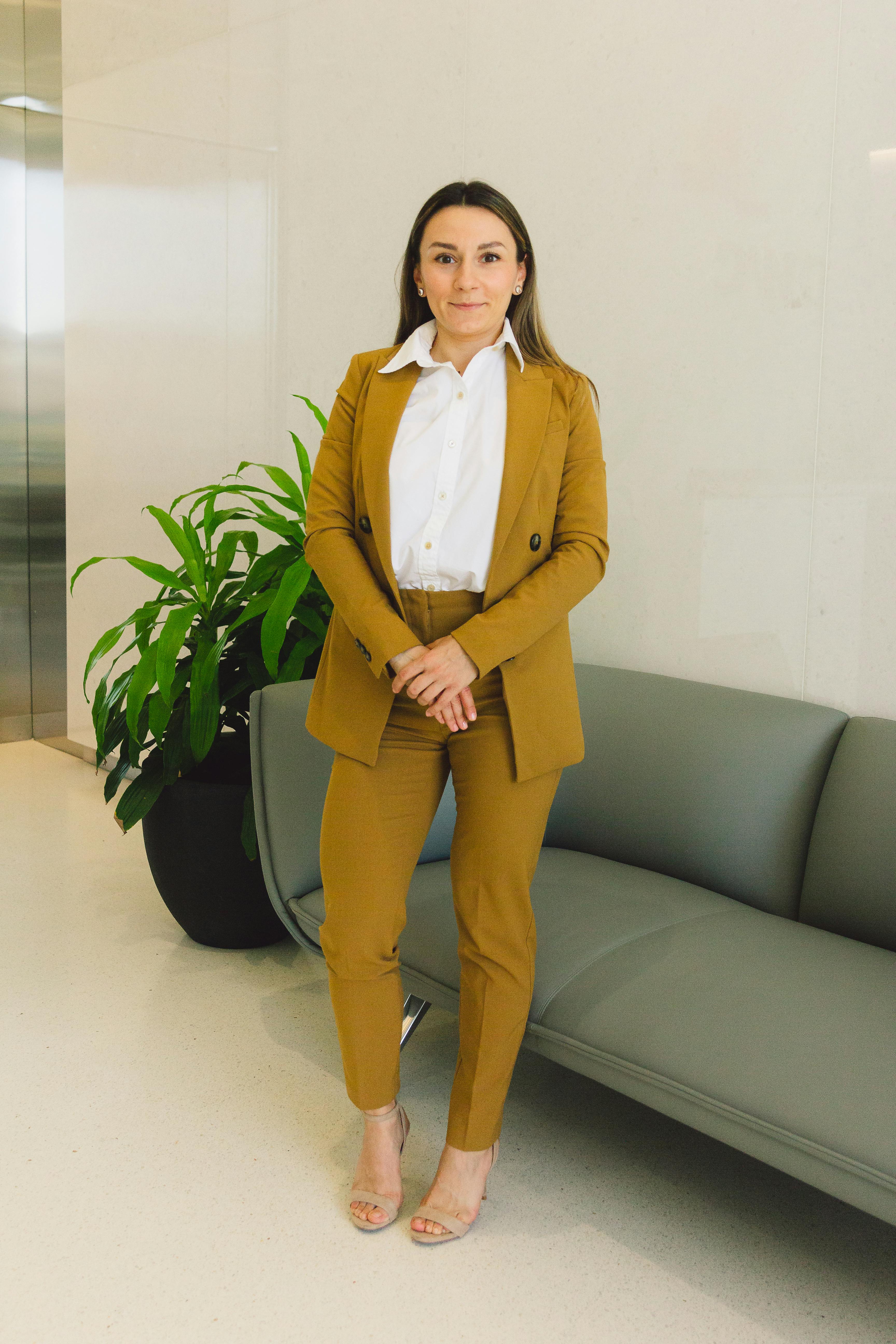 A Woman in Formal Attire Standing Beside the Couch · Free Stock Photo