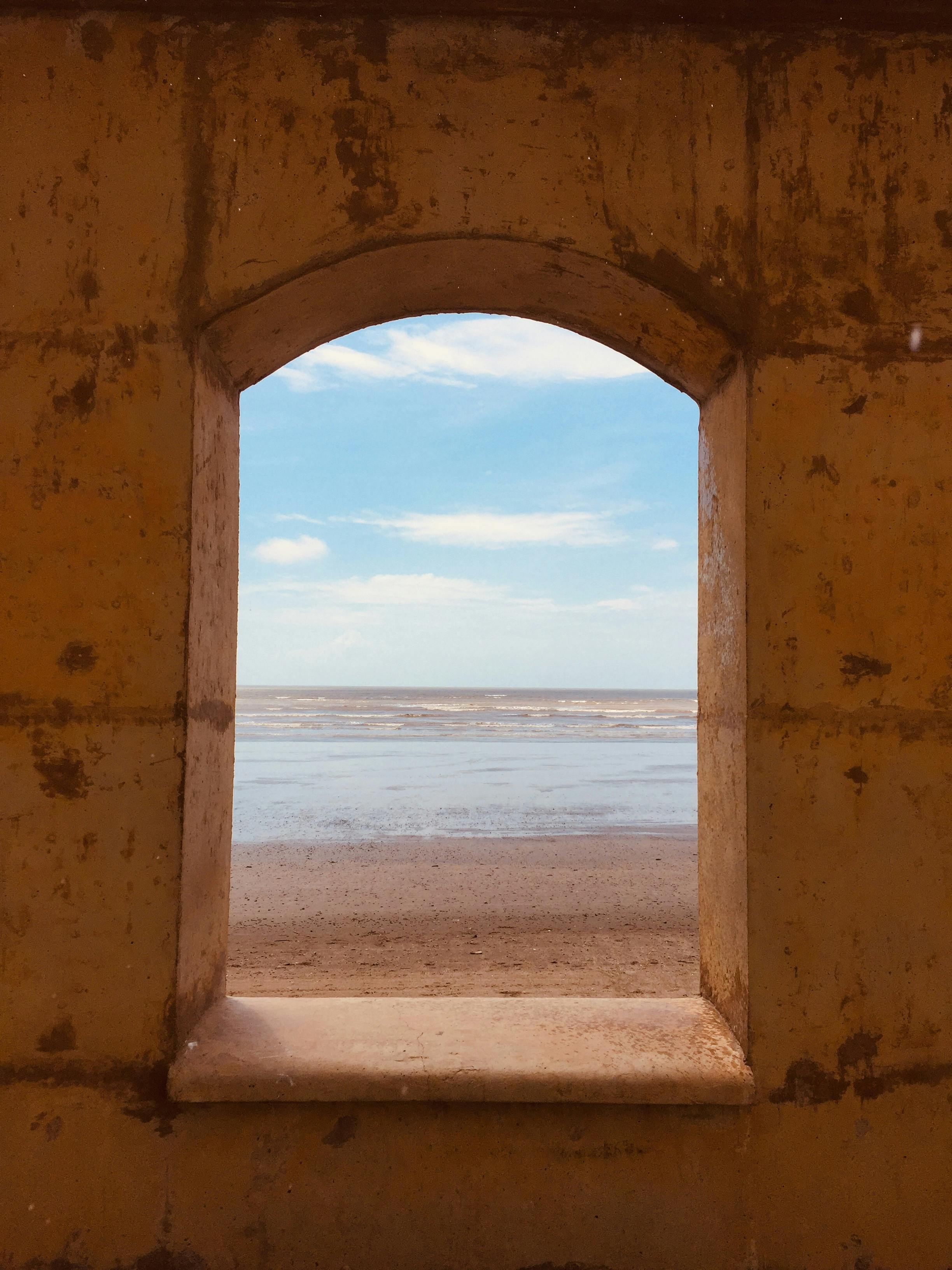 Stone Wall and Window with Sea Shore behind · Free Stock Photo