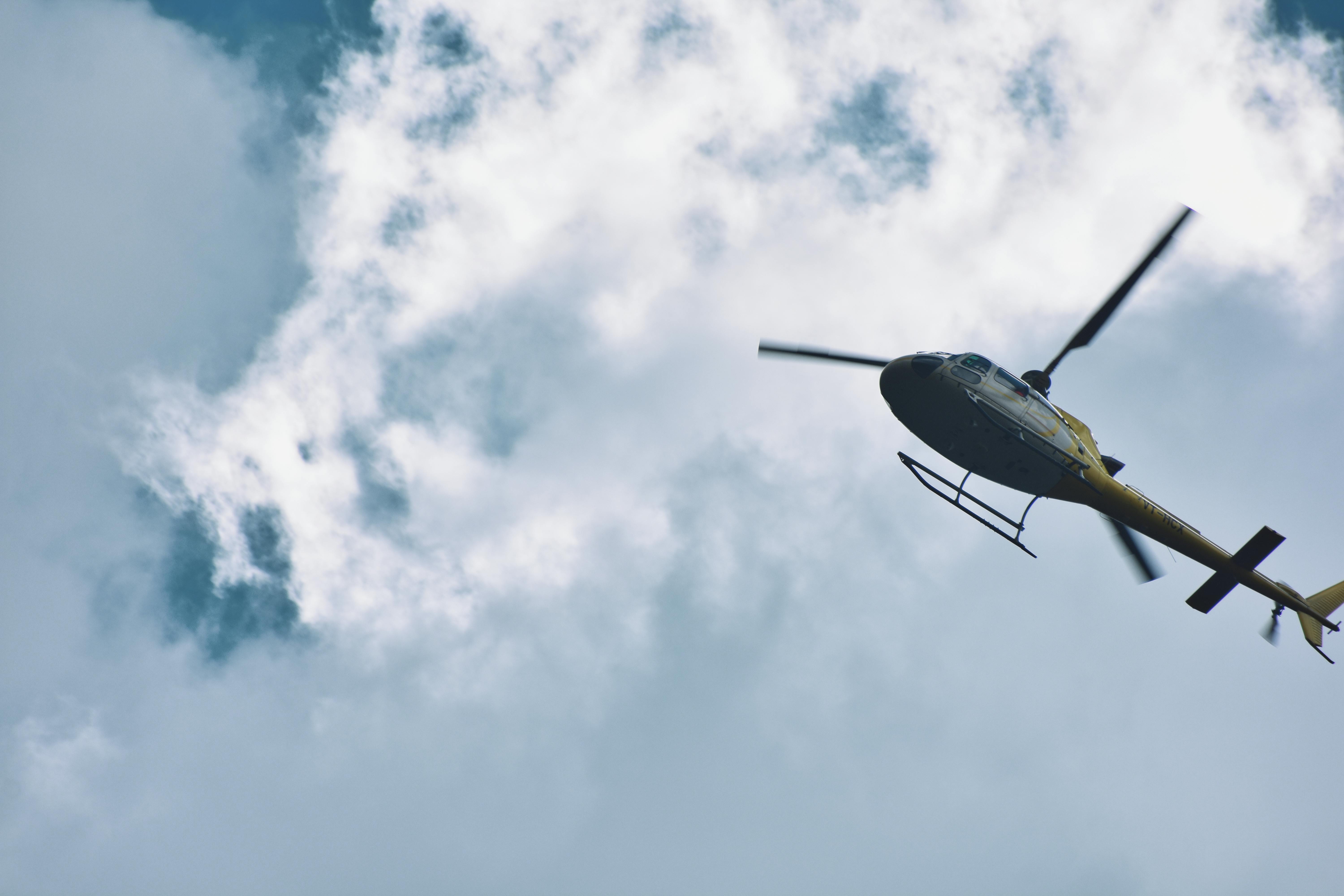Helicopter Flying Under White Clouds · Free Stock Photo