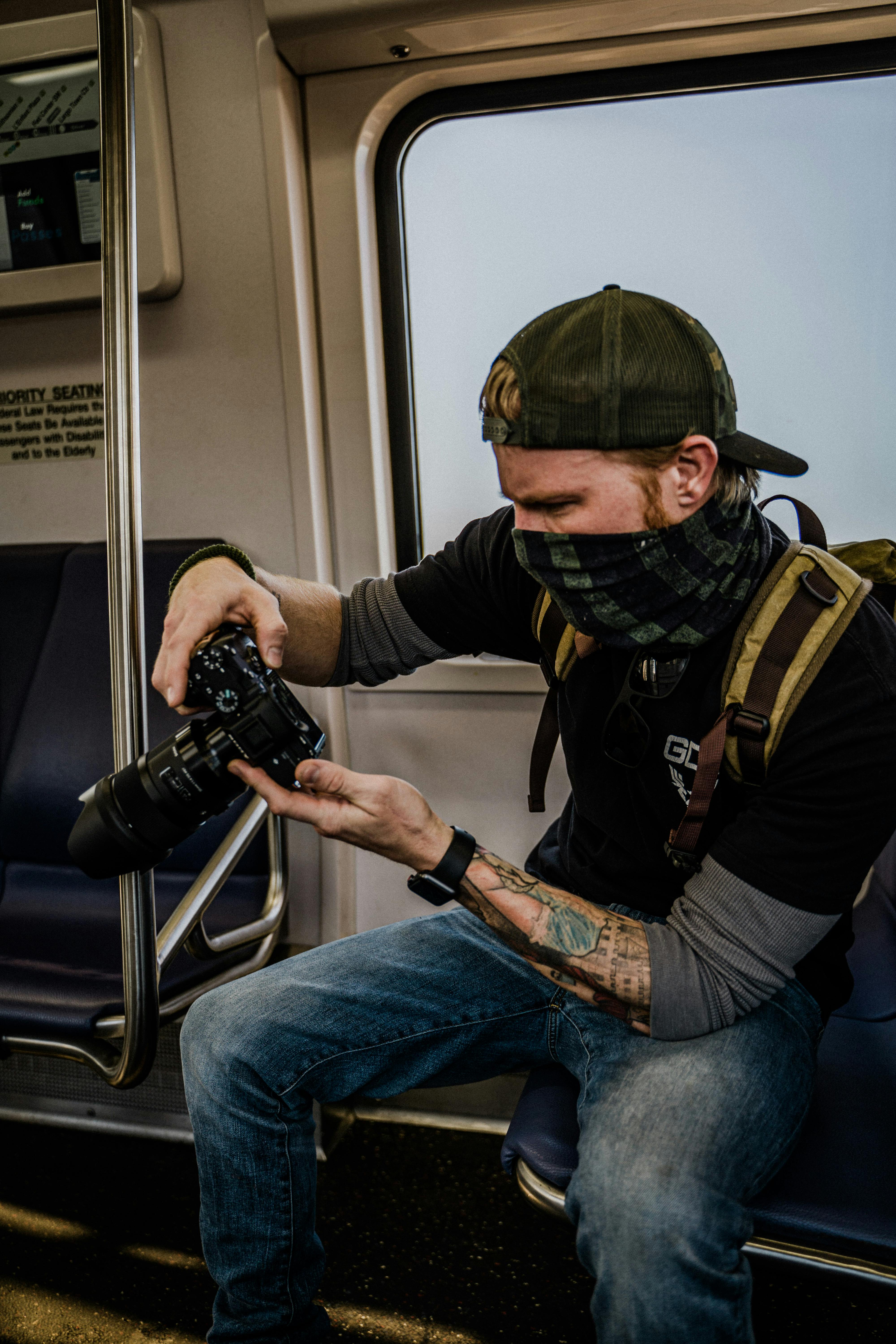 A Man Sitting Inside the Train while Holding a Black Camera · Free ...