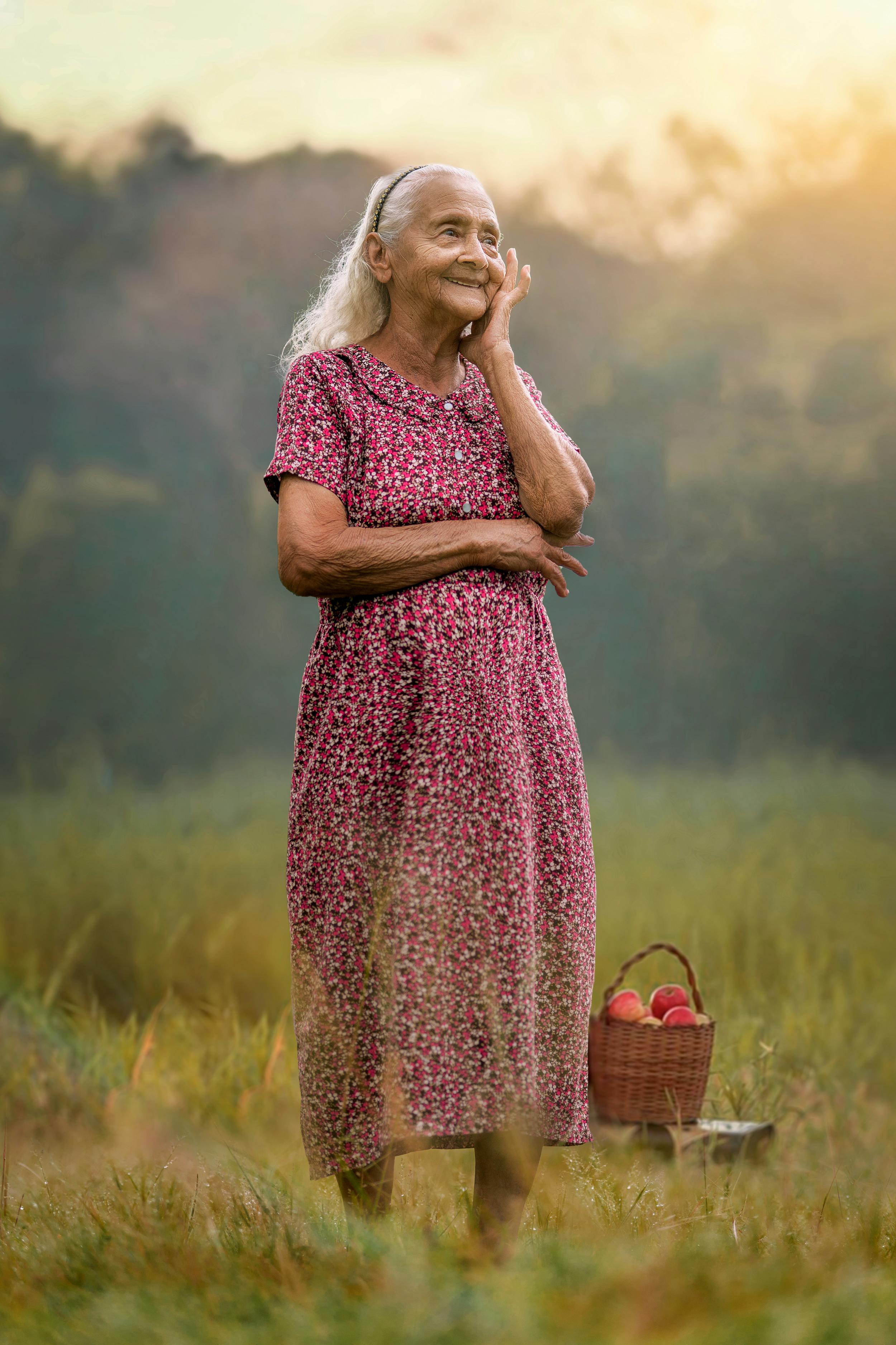 Elderly Woman in Floral Dress Standing in the Field · Free Stock Photo