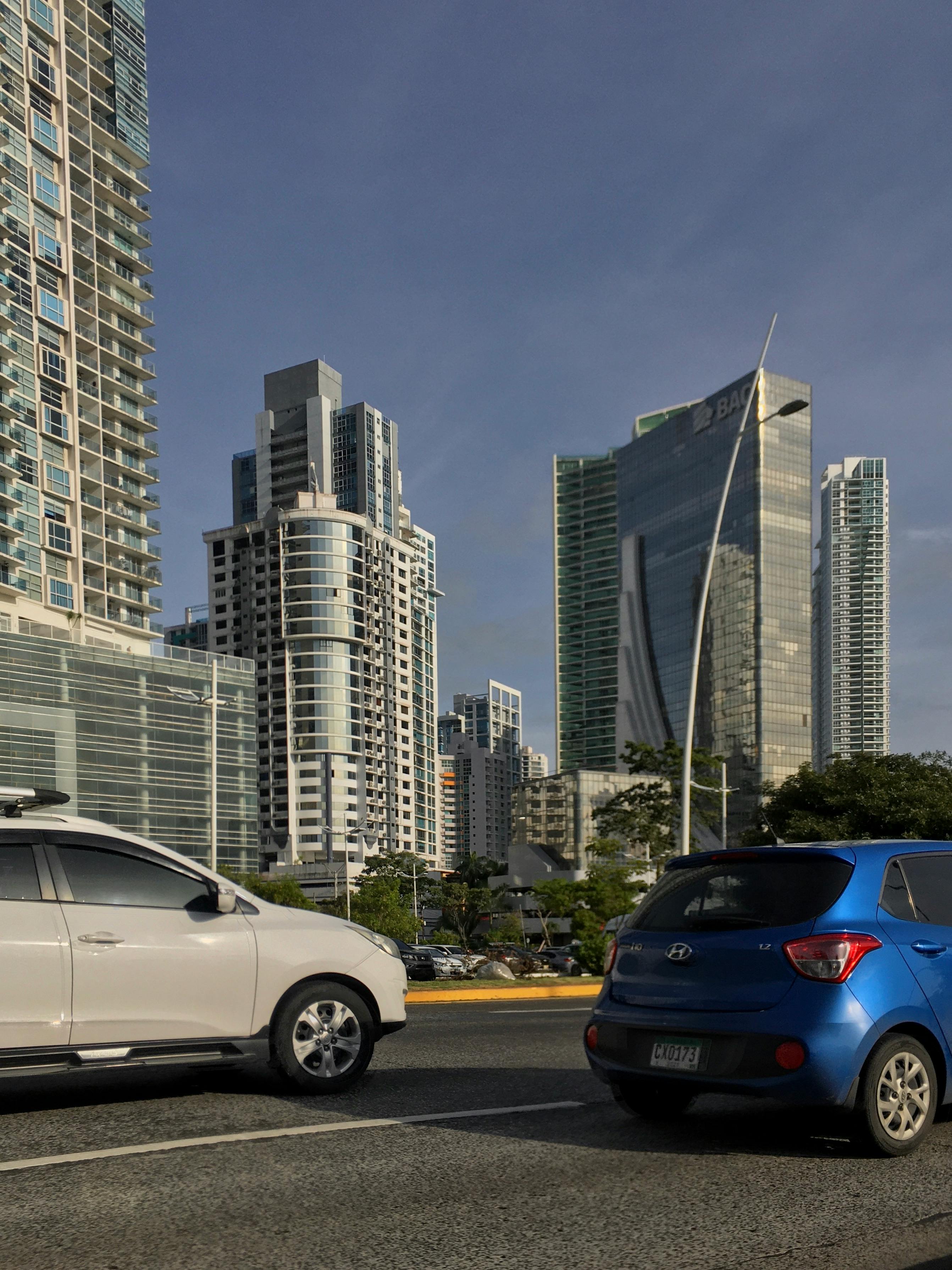 Photo of Two Cars Moving in Front of Skyscrapers · Free Stock Photo