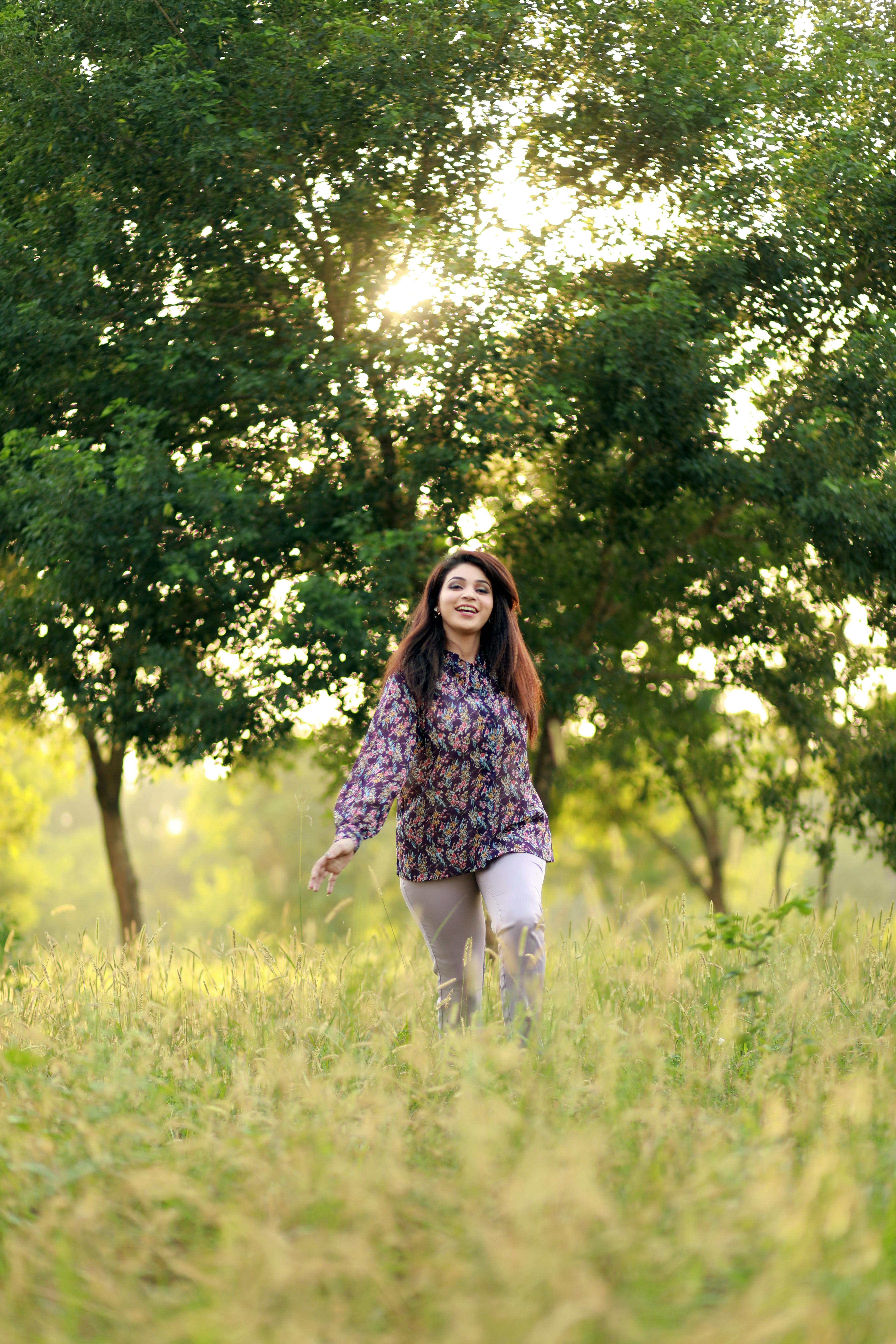 Woman Walking on Grass Field near Green Trees · Free Stock Photo