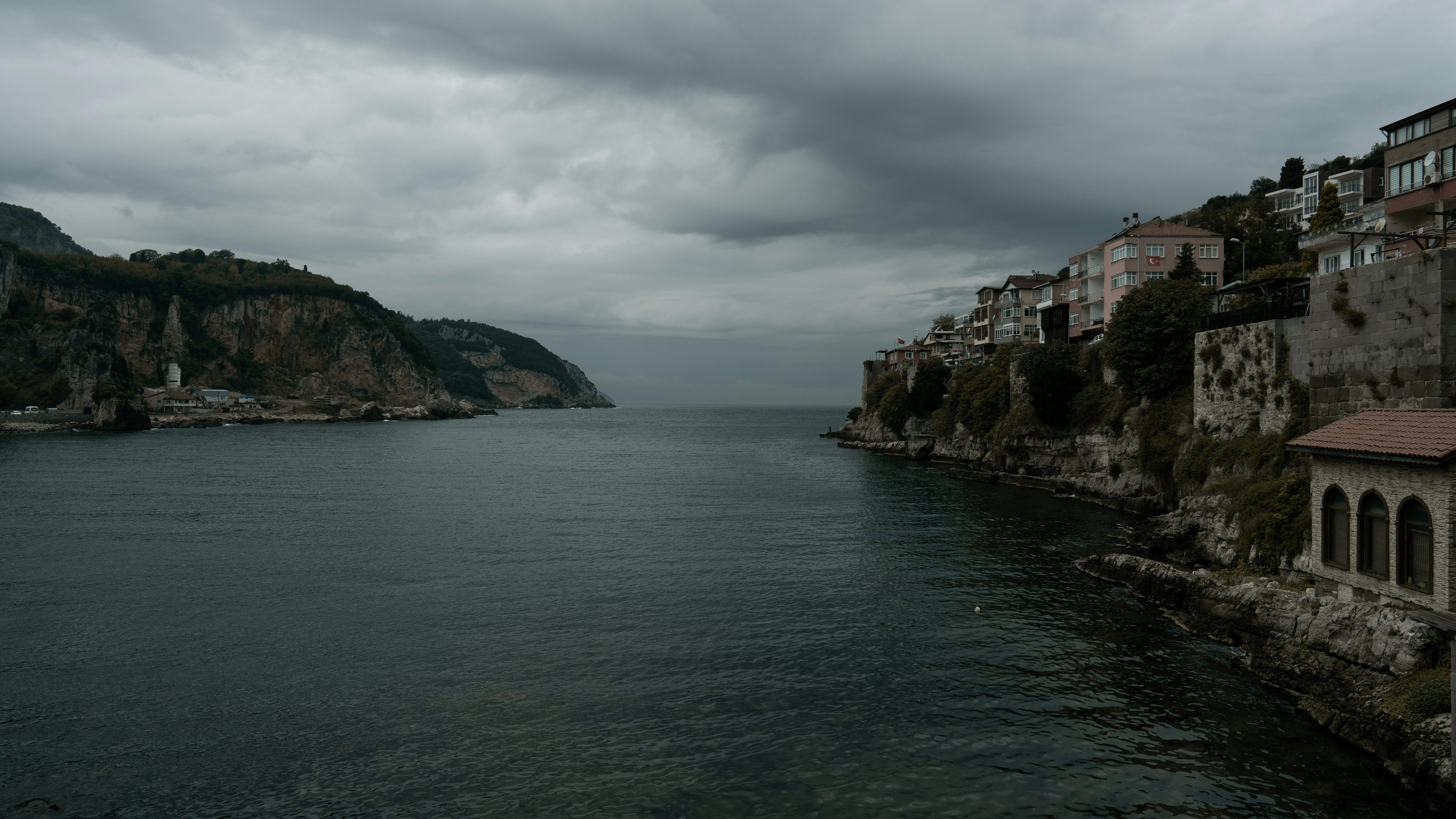 A Sea Near an Island with Buildings Under Gray Skies · Free Stock Photo
