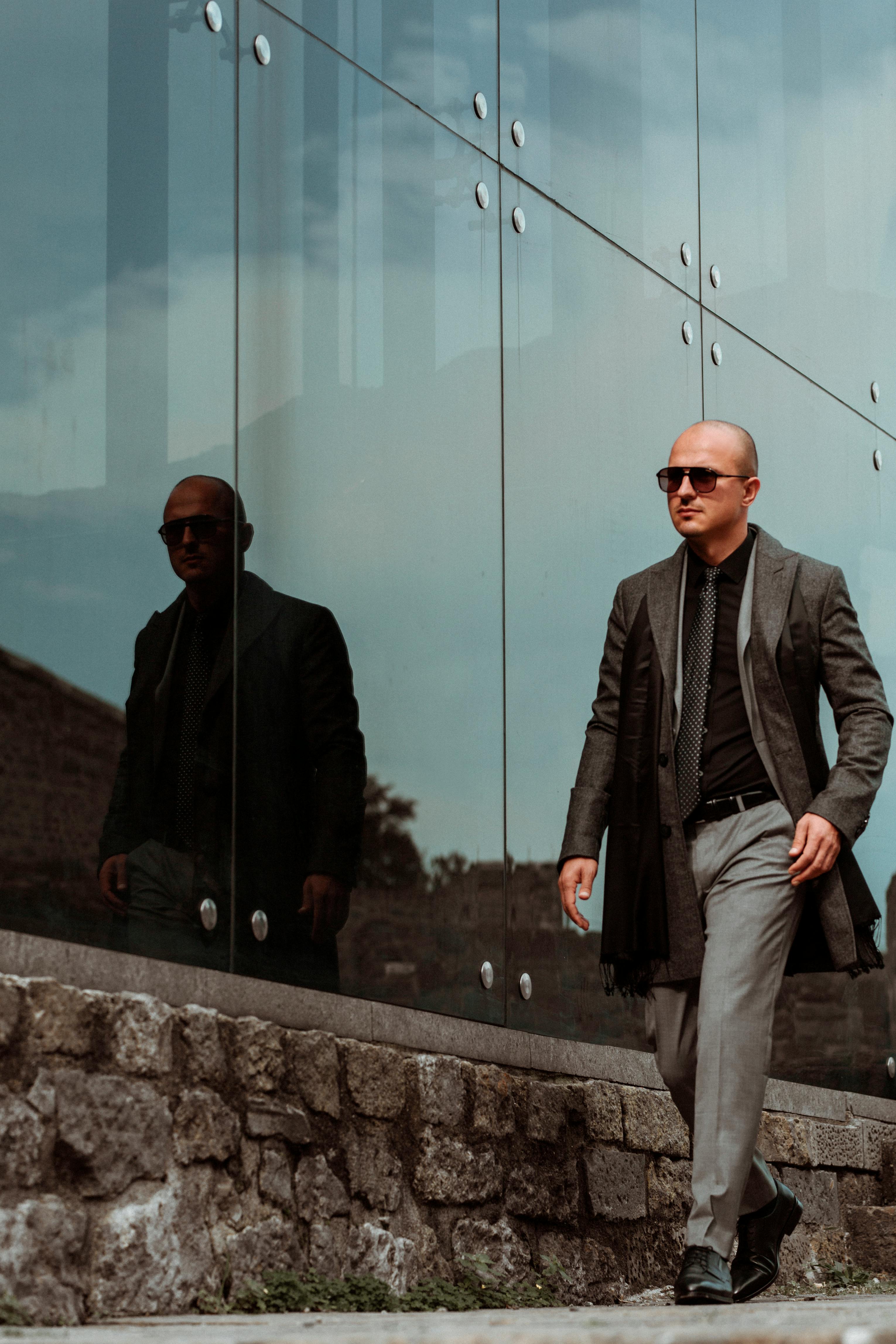 Man in Black Coat Walking Near Glass Windows · Free Stock Photo