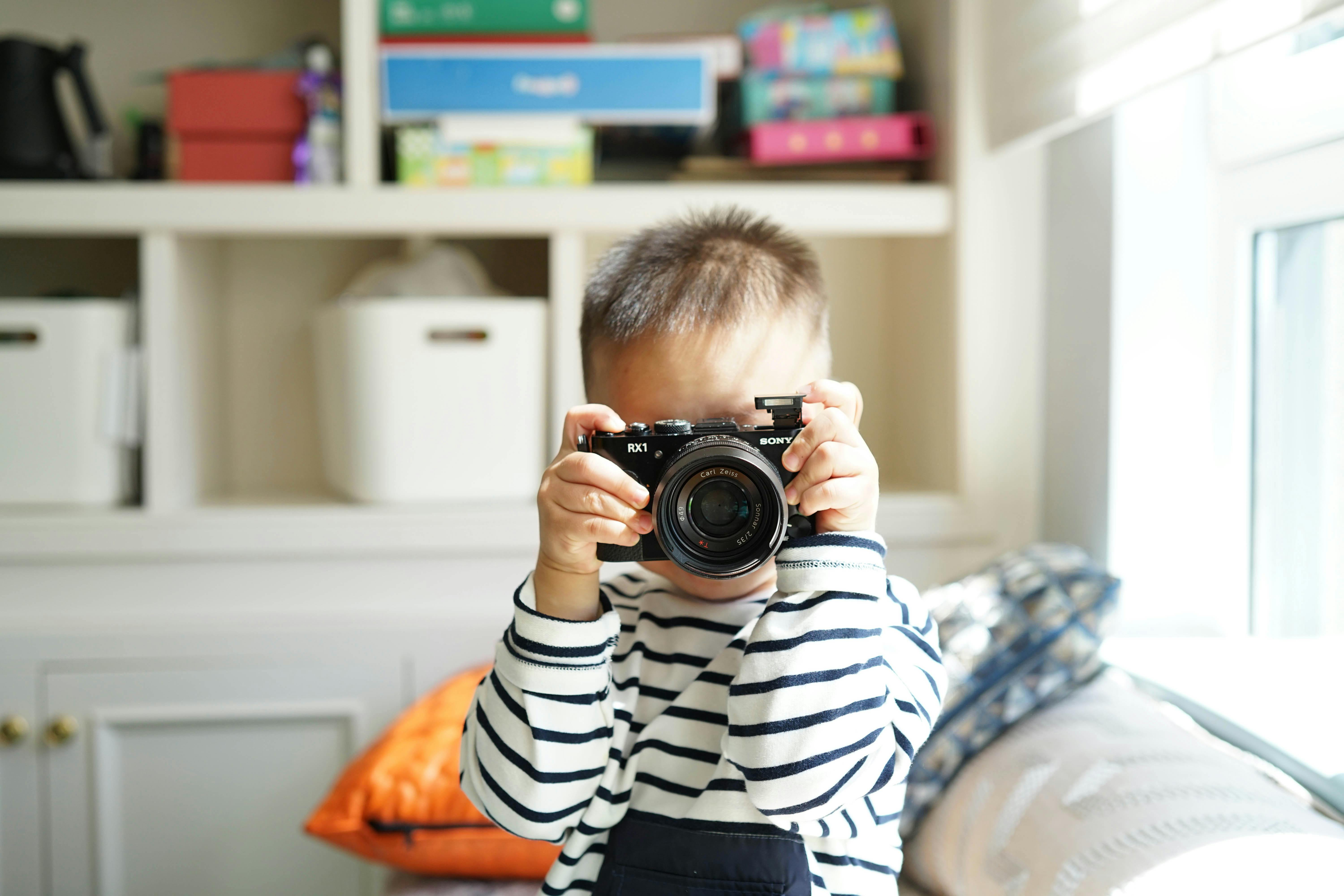 A Boy Holding a Black Dslr Camera · Free Stock Photo