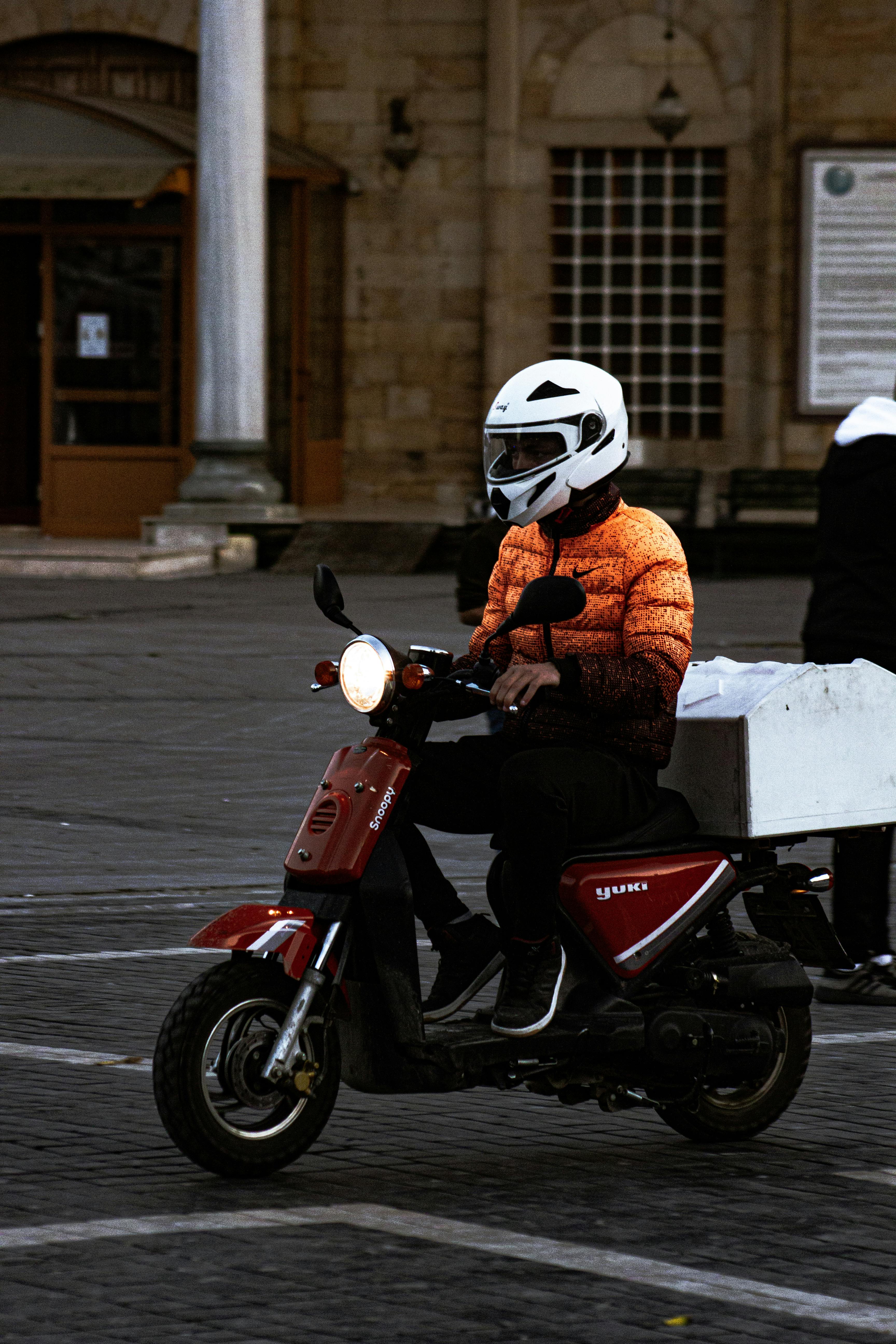 Person in Orange Jacket Riding Red Motor Scooter · Free Stock Photo