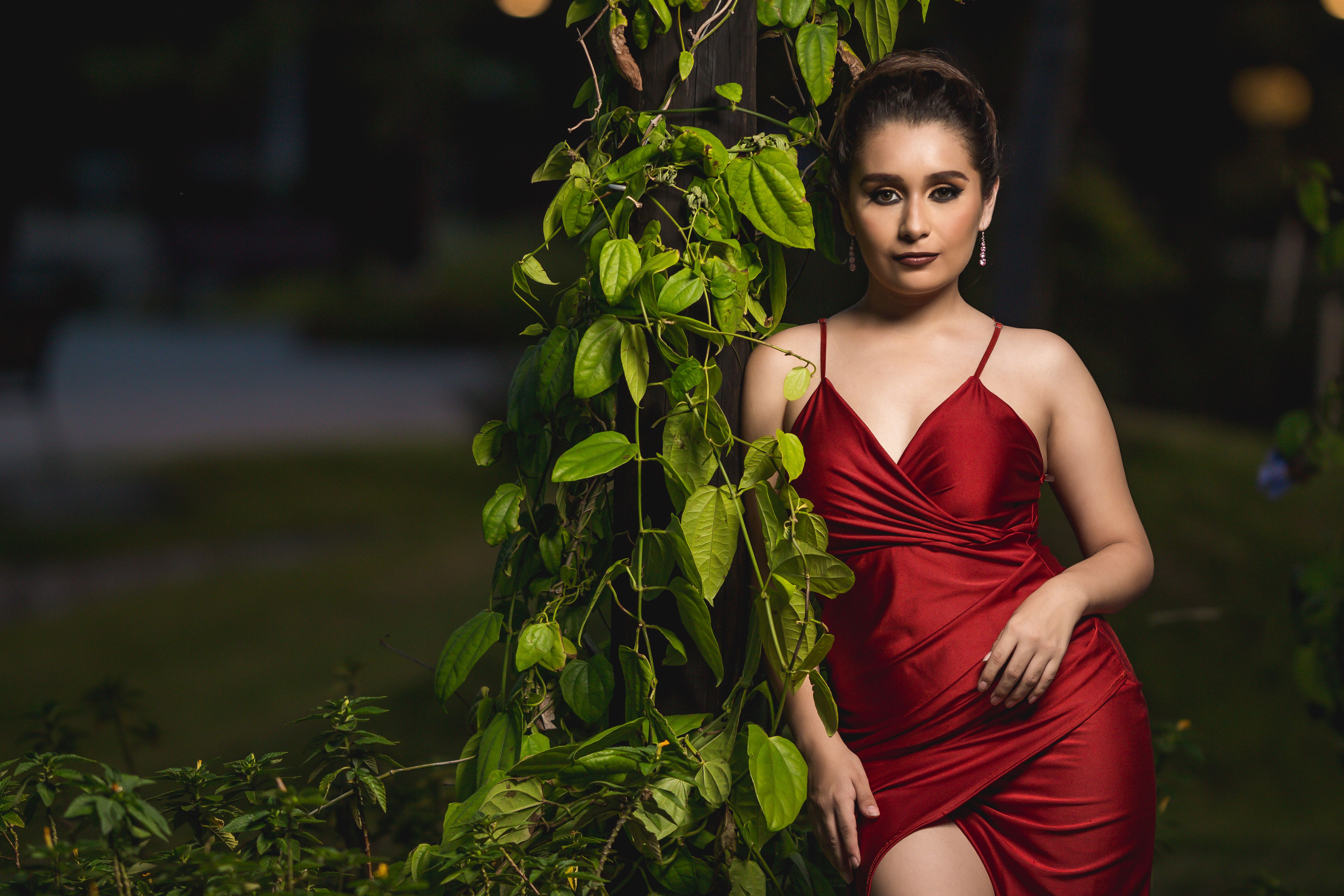 Beautiful Woman in Red Dress Posing near Green leaves · Free Stock Photo