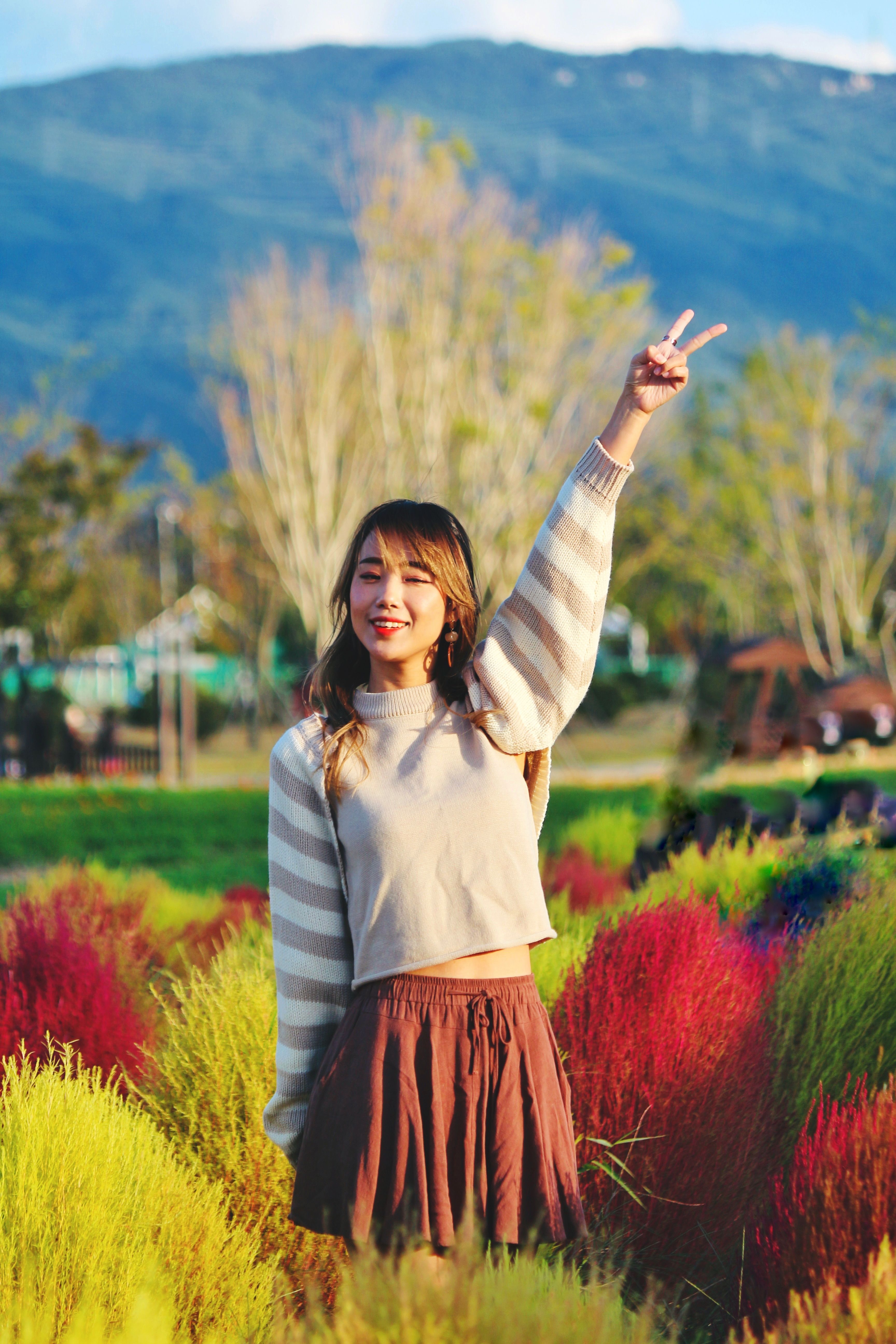 A Woman Doing Peace Sign While Standing in a Field · Free Stock Photo