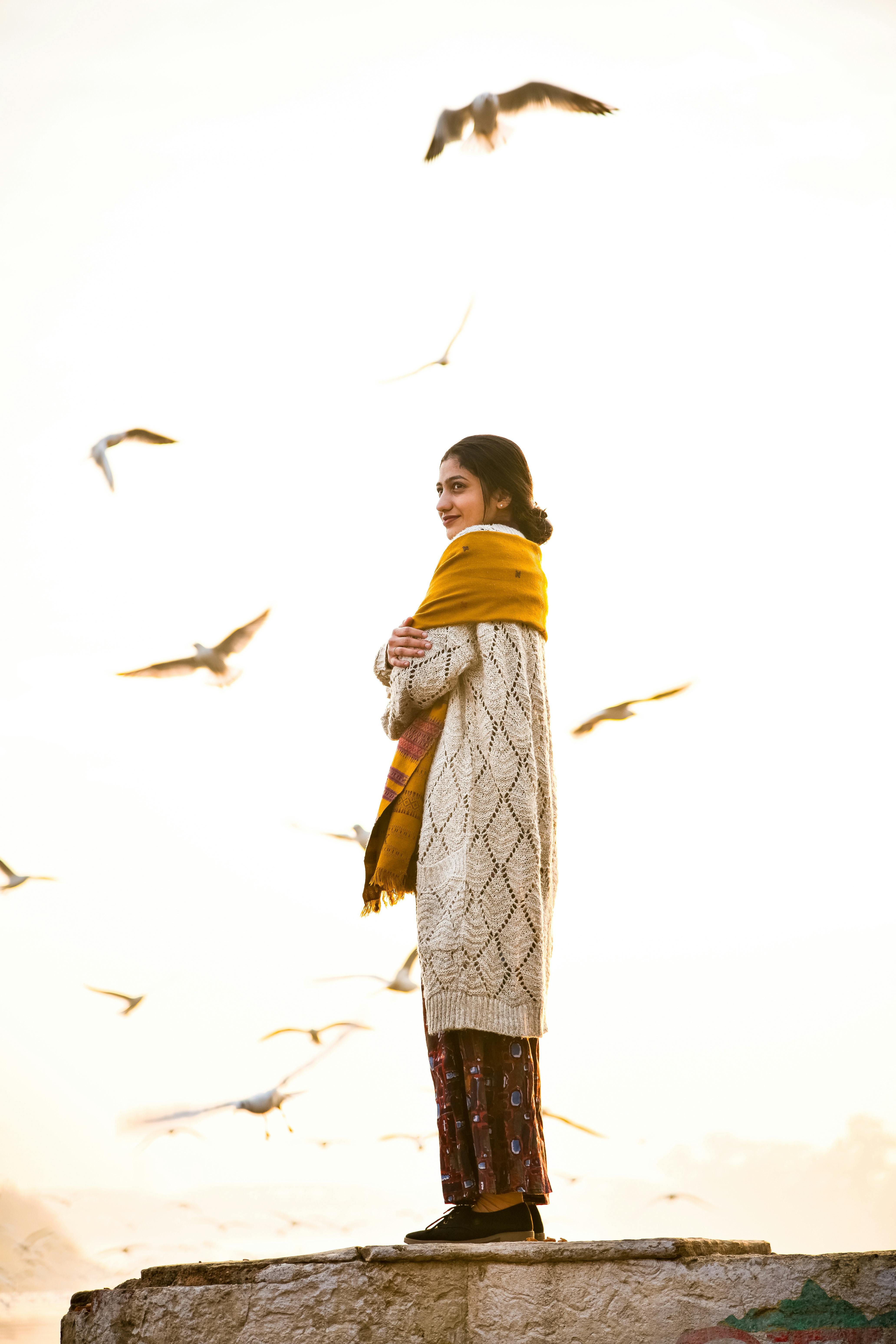 Woman Standing on Ledge Looking at Flying Birds · Free Stock Photo