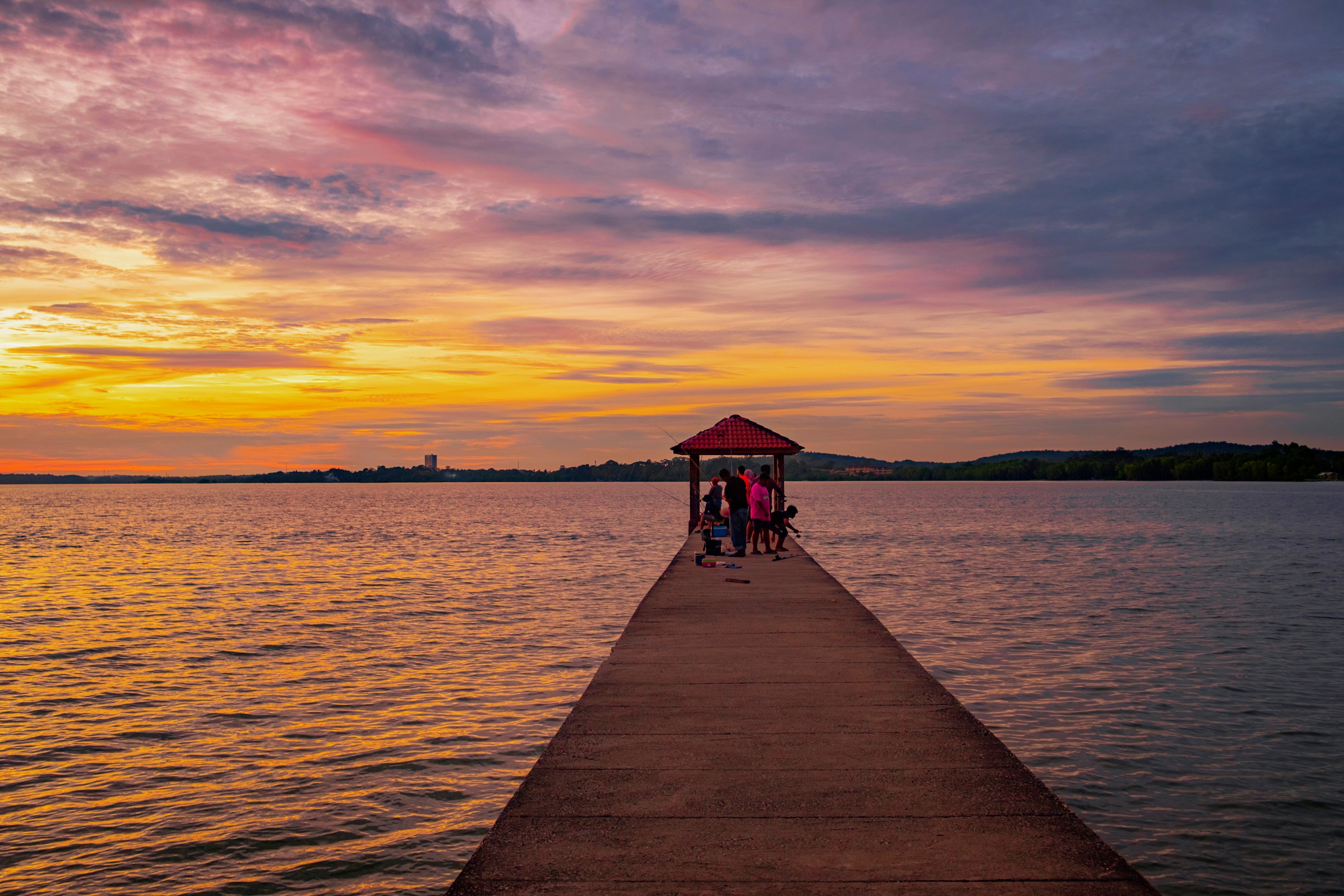 People on Concrete Dock near Ocean during Sunset · Free Stock Photo