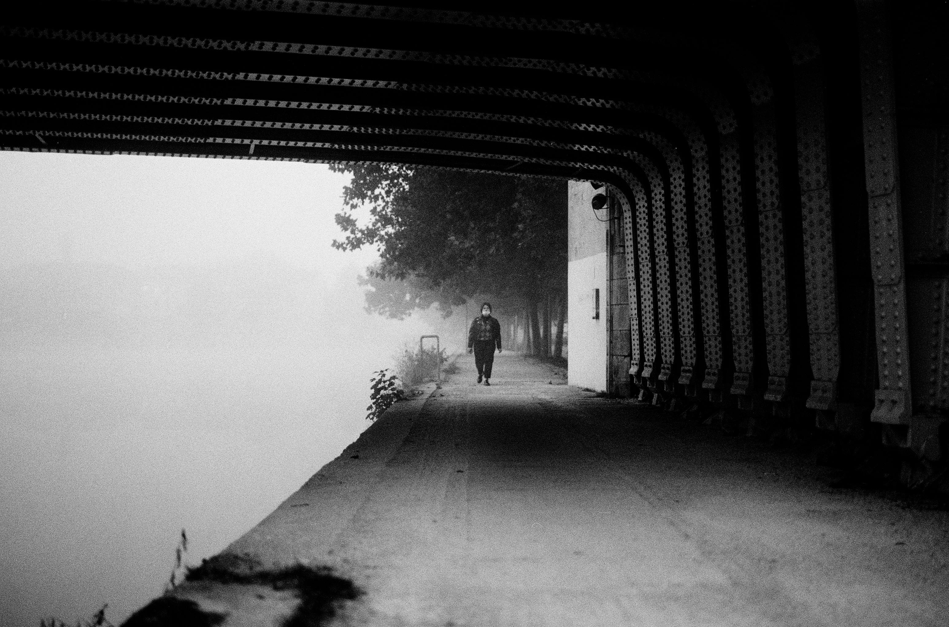 Grayscale Photo of a Person Walking Under the Bridge · Free Stock Photo
