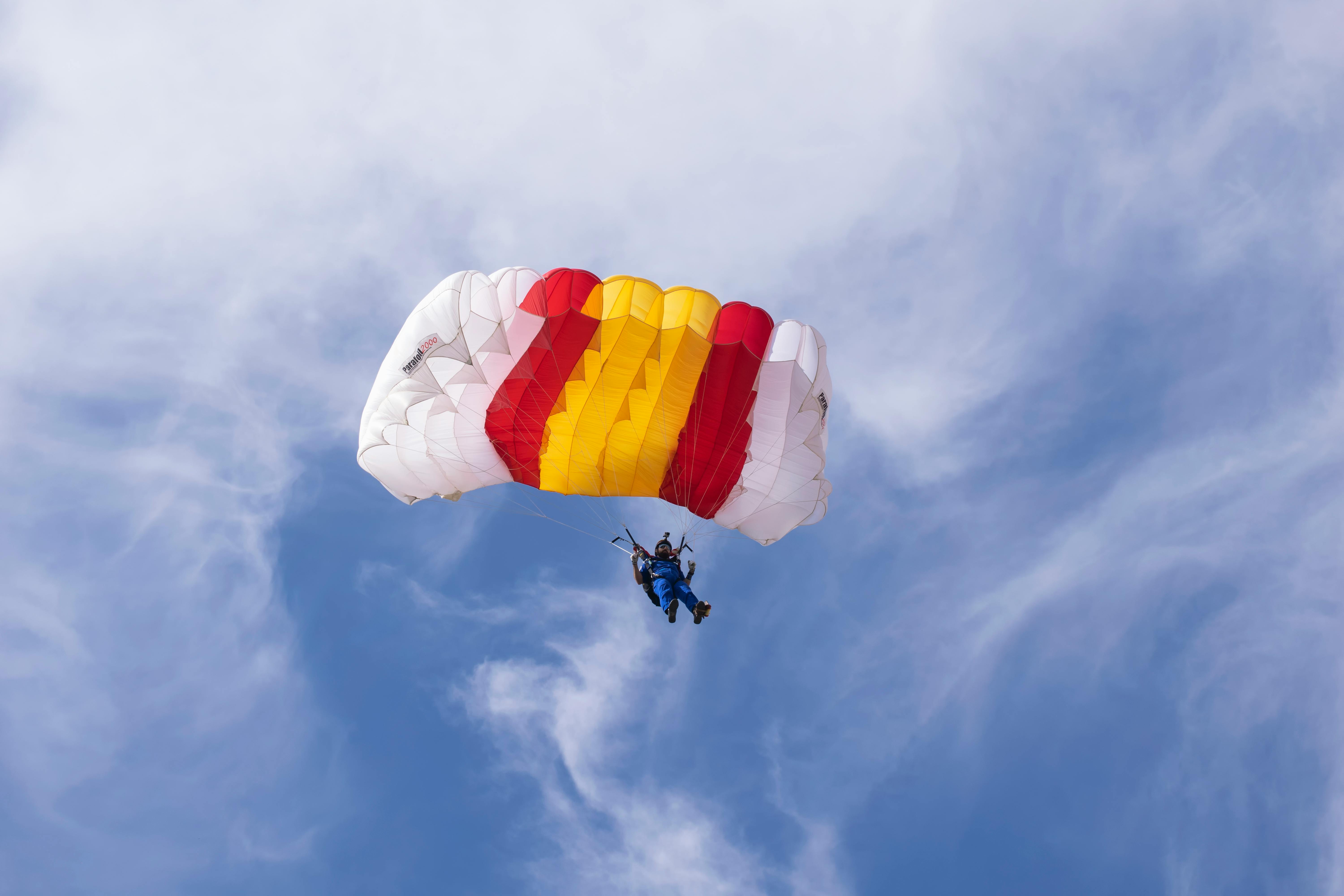Low Angle Shot of a Man Falling with a Parachute · Free Stock Photo