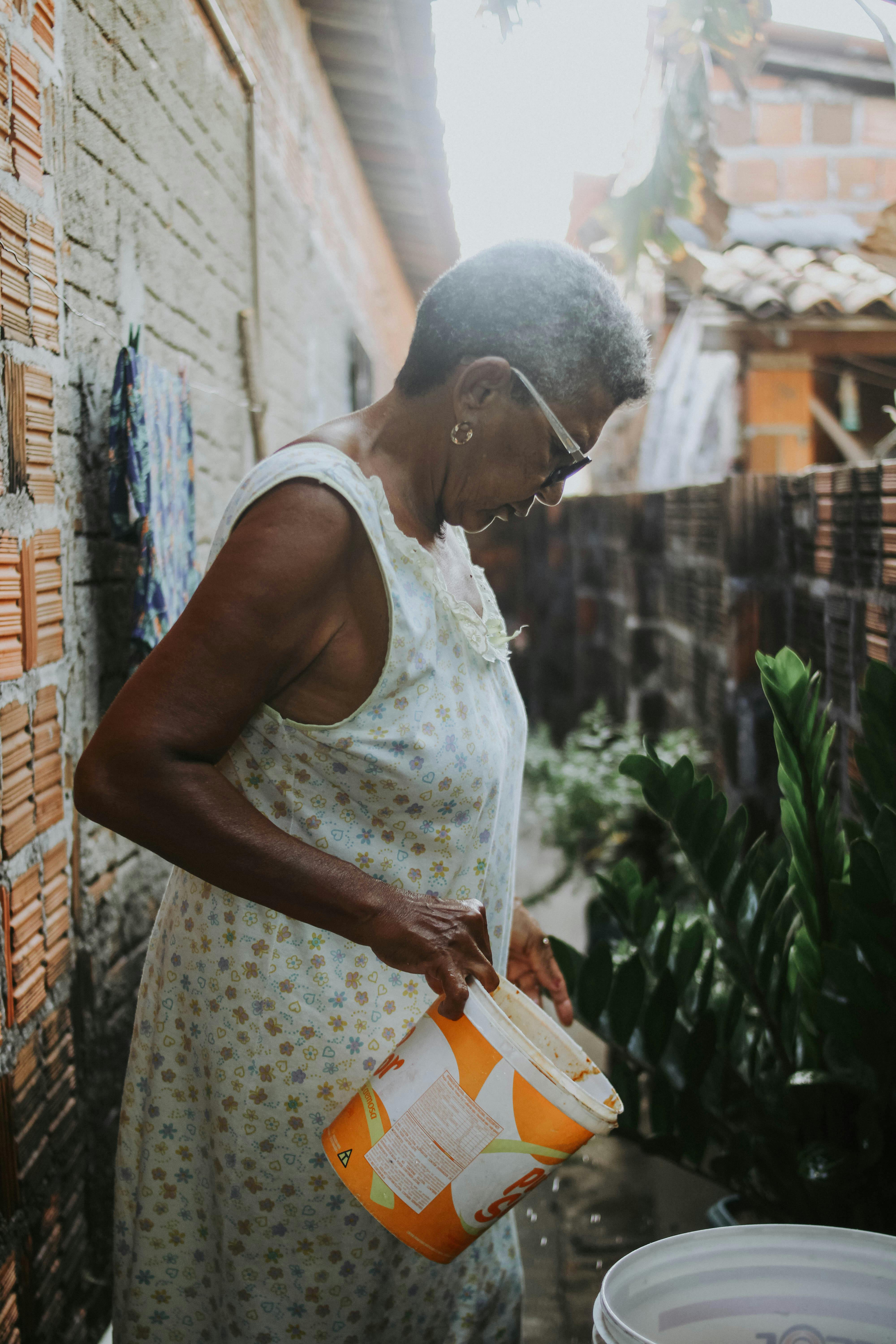 A Woman Holding White and Orange Bucket · Free Stock Photo
