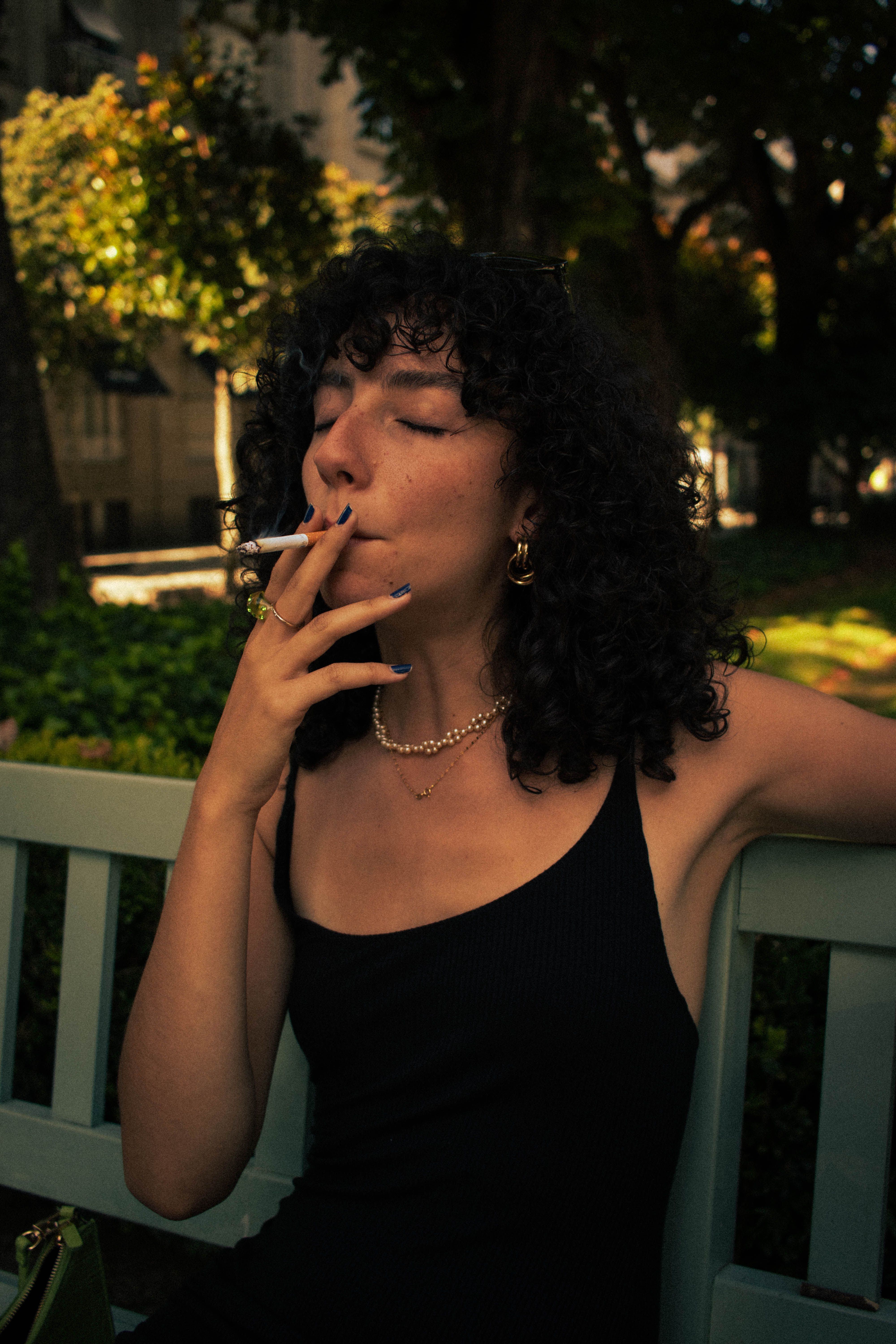Woman Smoking a Cigarette while Sitting on a Bench · Free Stock Photo