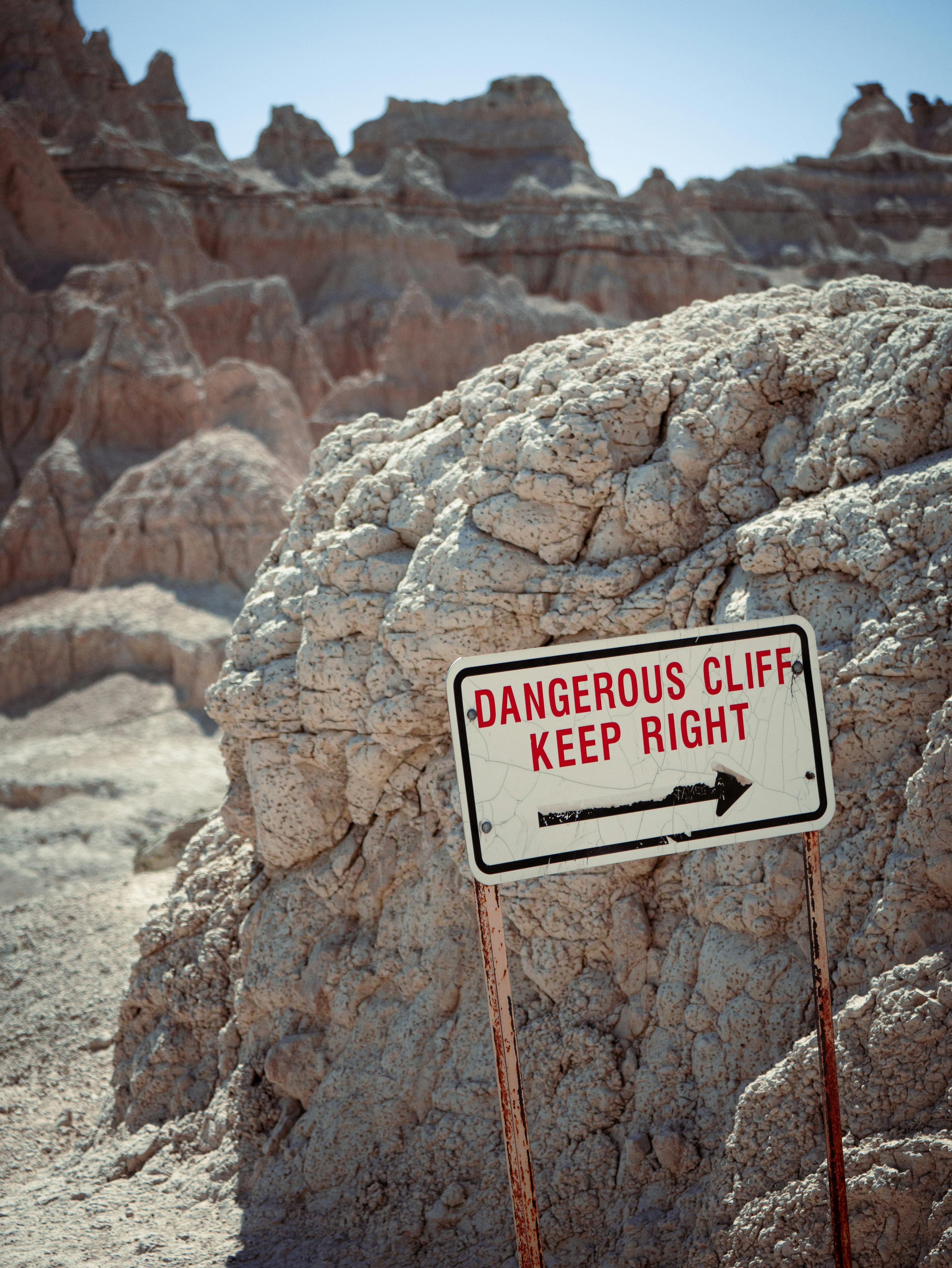Damaged Sign near a Rock Formation · Free Stock Photo