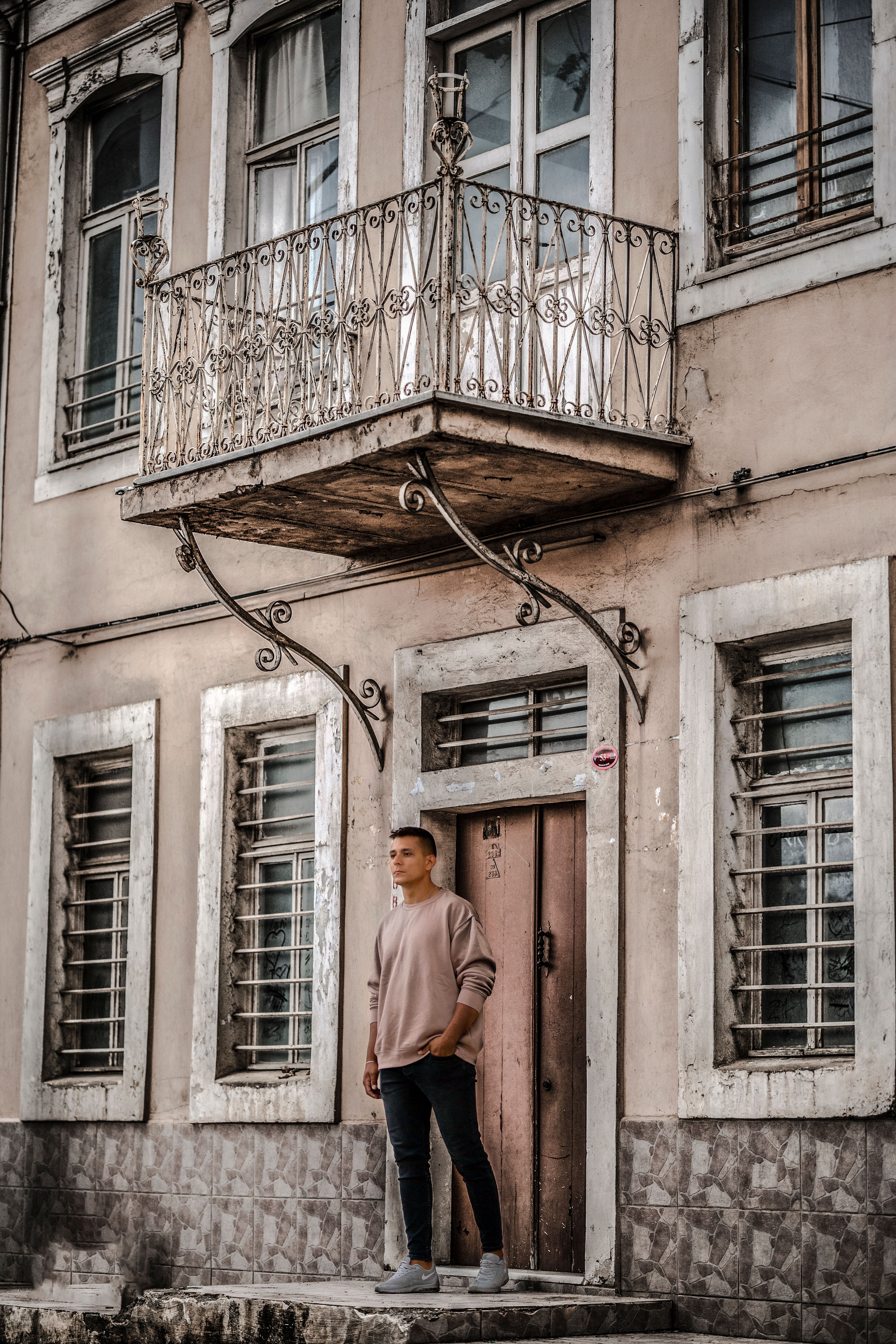 Man Standing in front of an Old Tenement House in City · Free Stock Photo