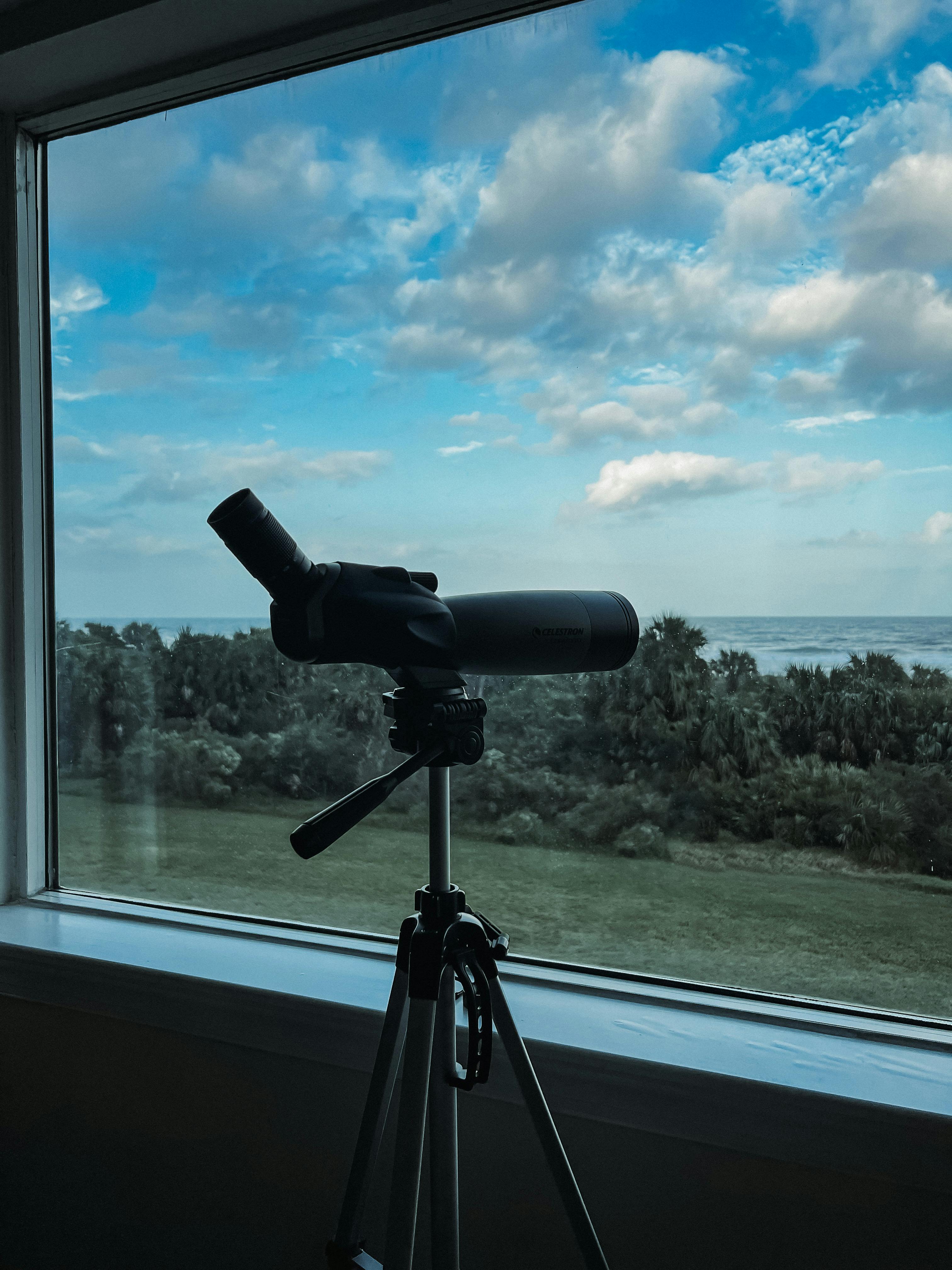 Telescope on a Tripod Near Glass Window · Free Stock Photo