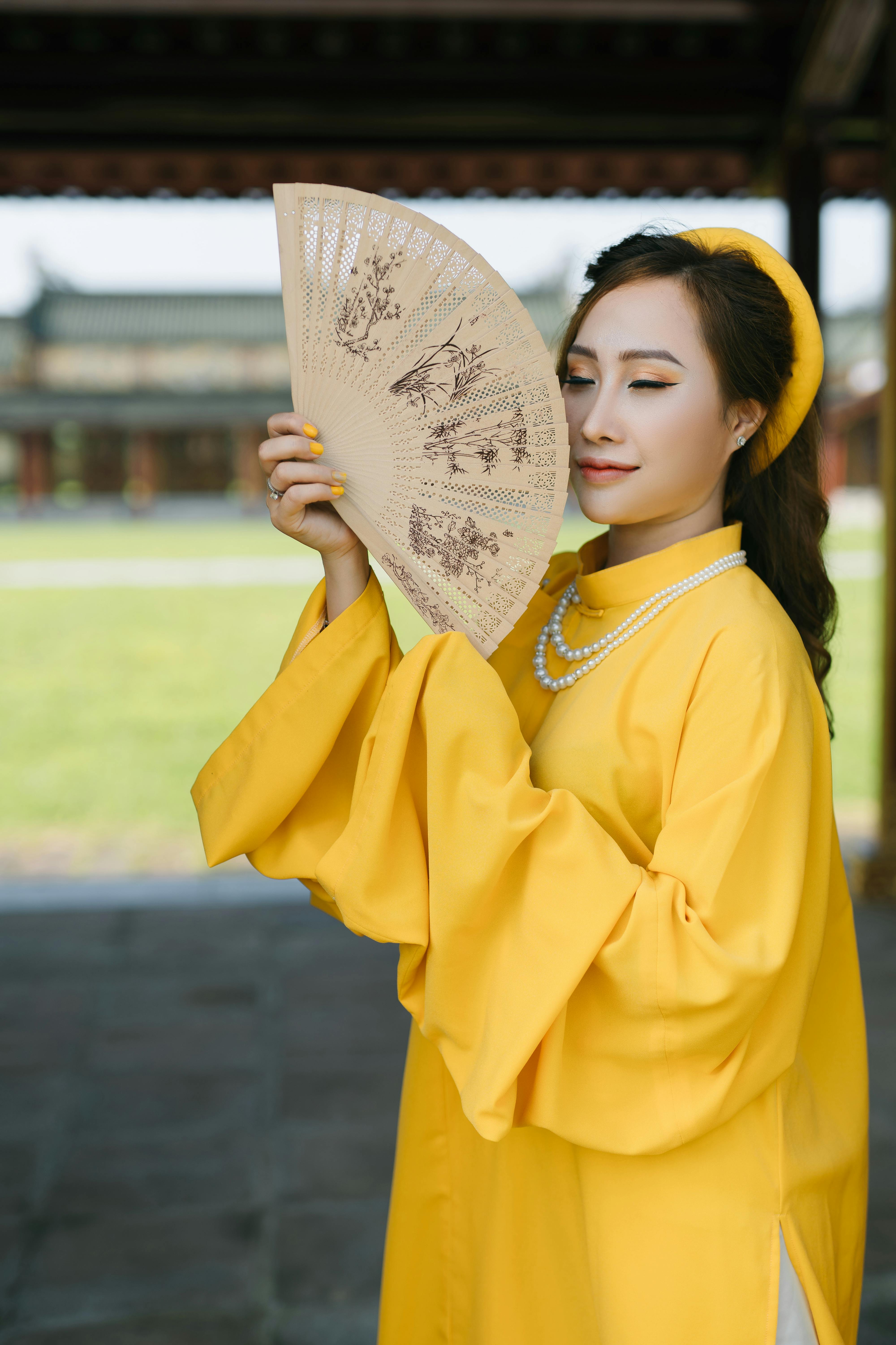 Beautiful Woman Posing with a Bamboo Hand Fan · Free Stock Photo