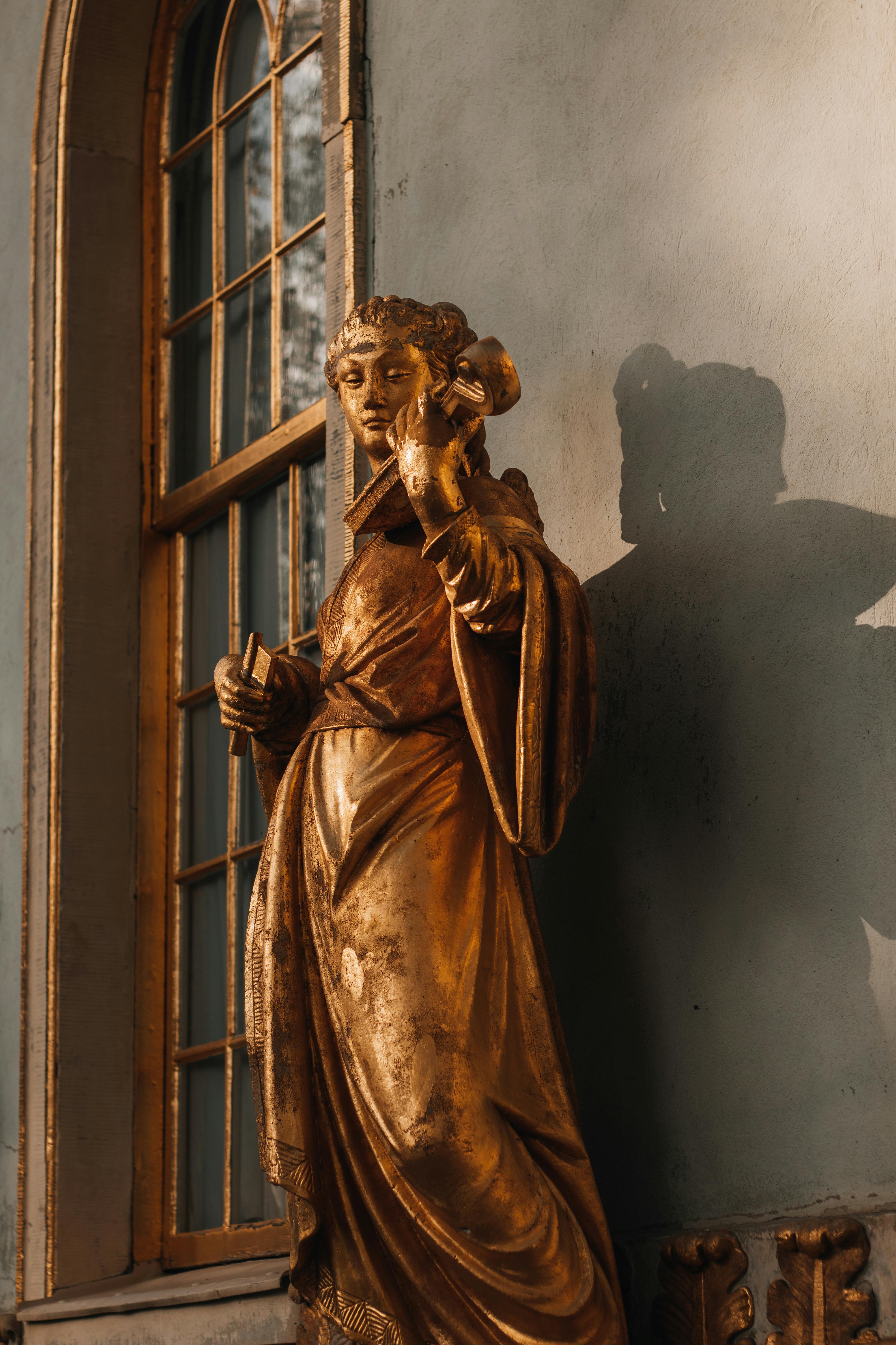Golden Statue Beside a Window · Free Stock Photo
