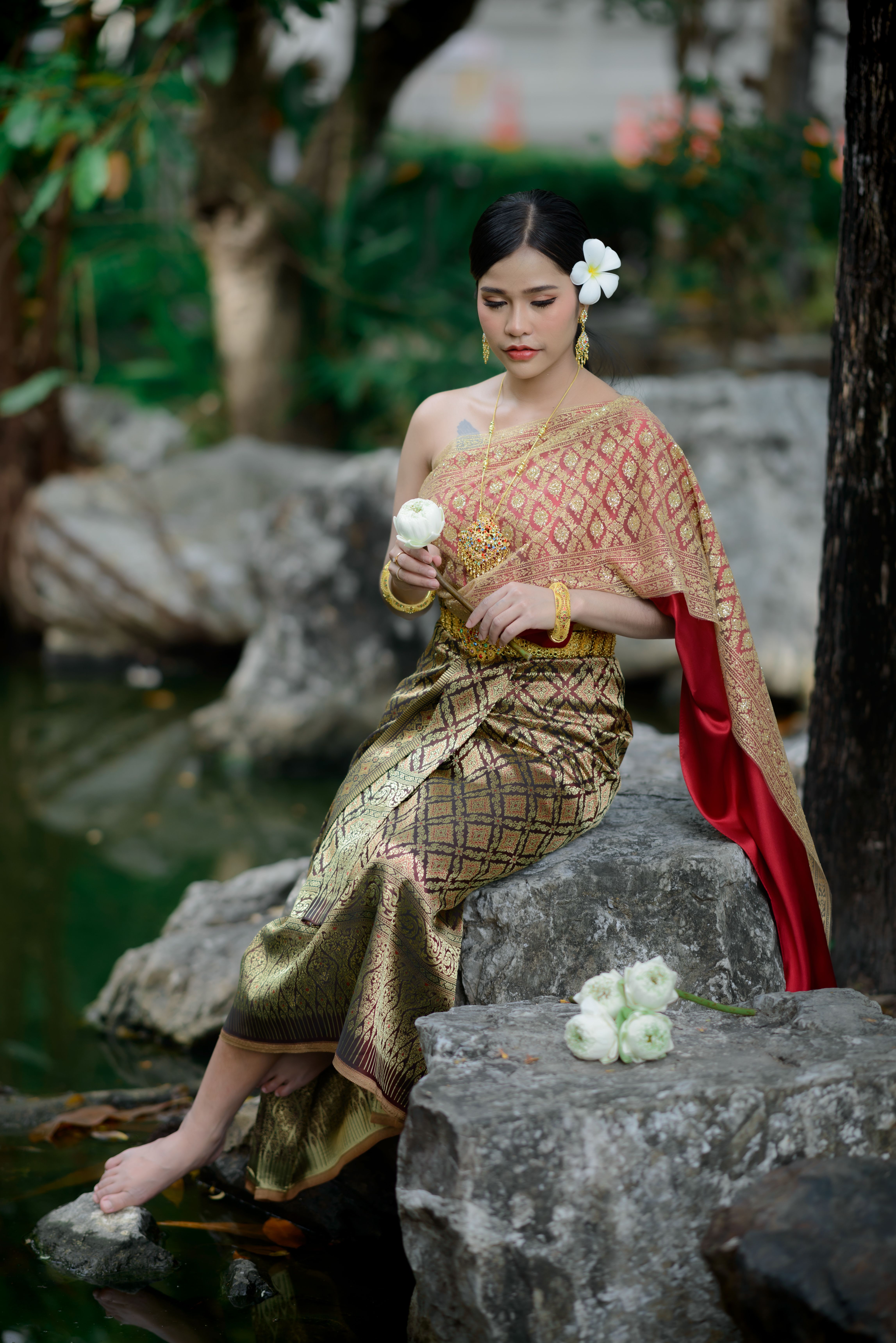 Woman in Thai Traditional Dress Sitting on Rock Holding a Flower · Free ...