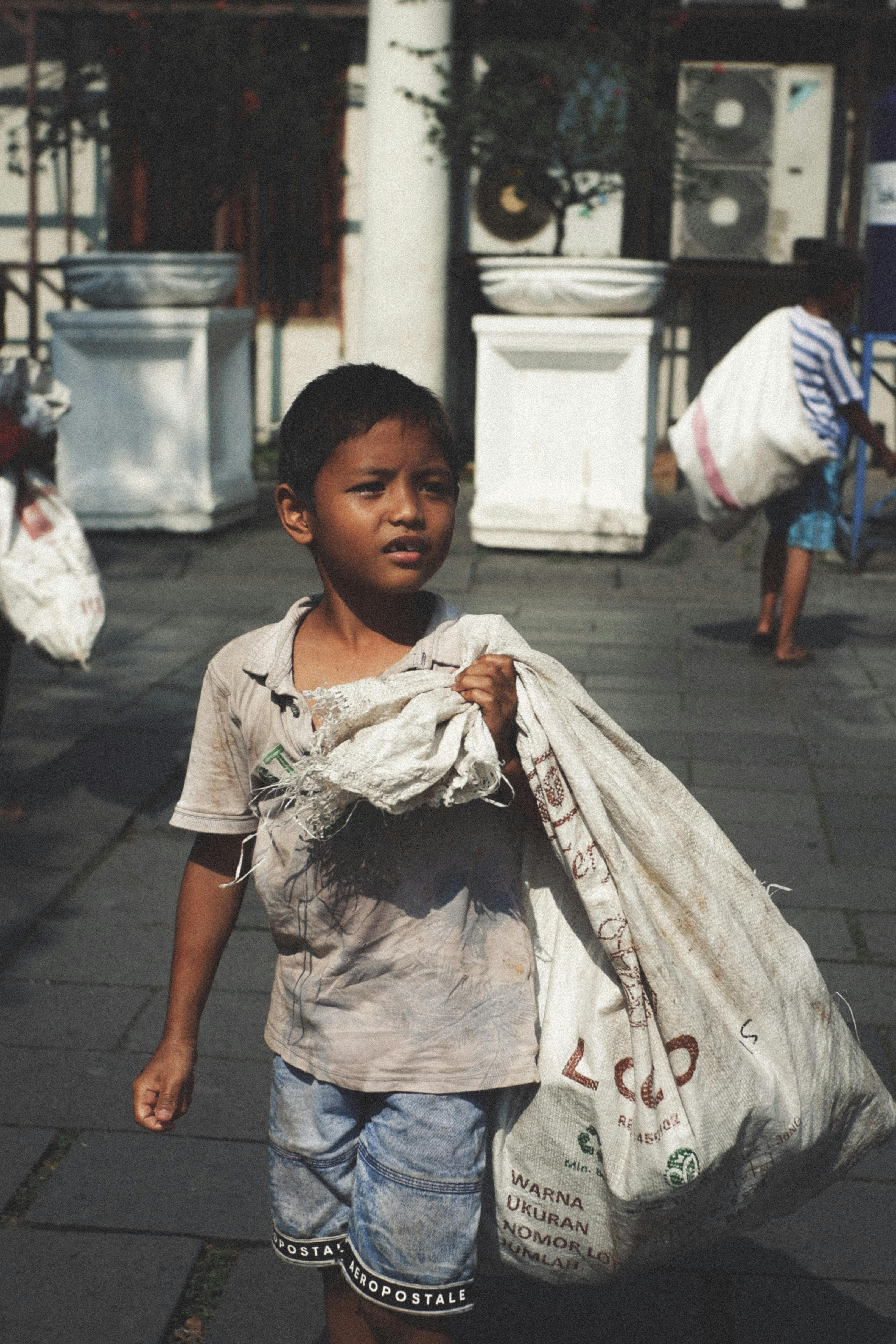 Photo of a Boy Carrying a Sack · Free Stock Photo