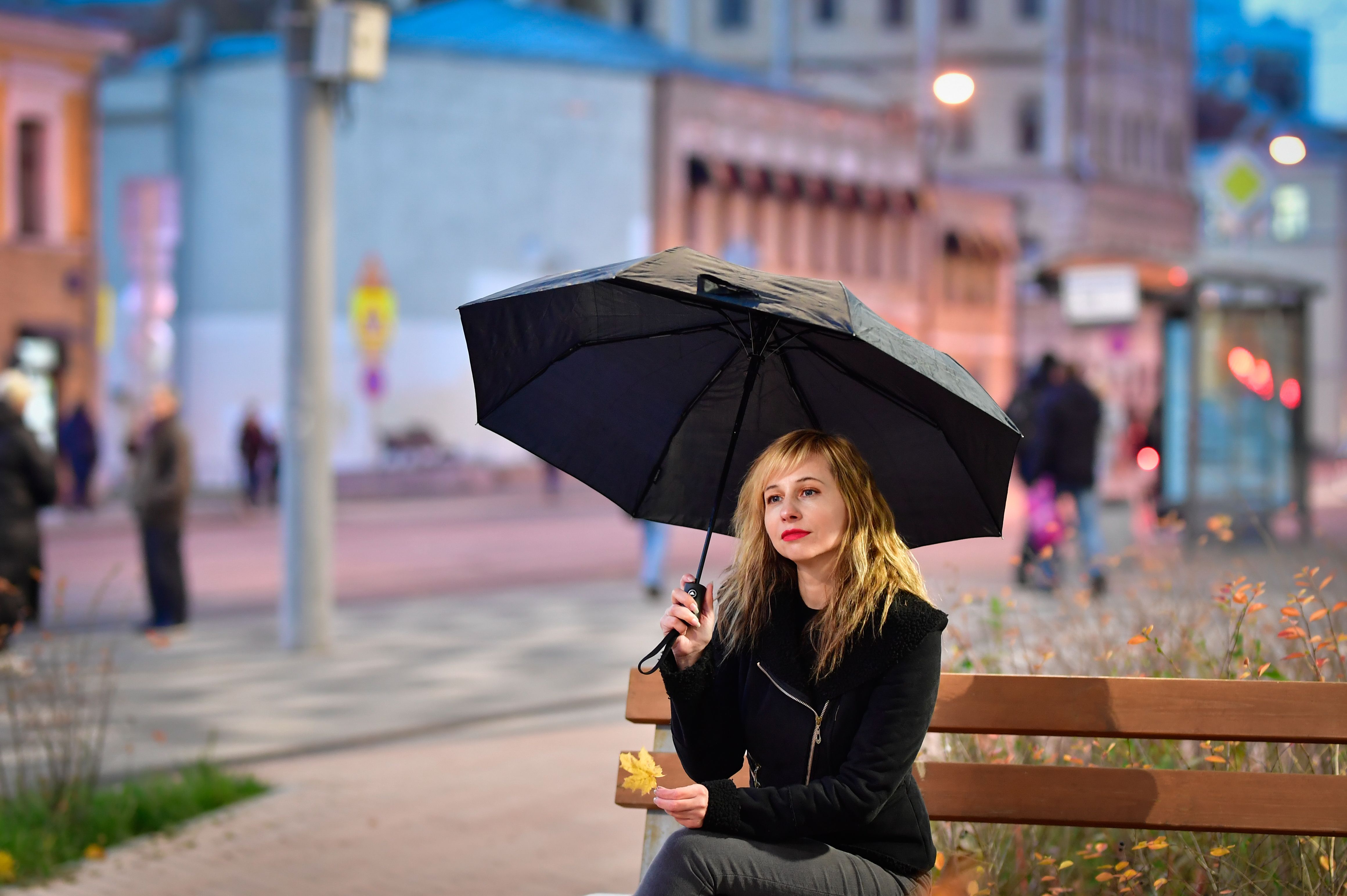 Woman with Umbrella Sitting on Bench with Coaches behind · Free Stock Photo