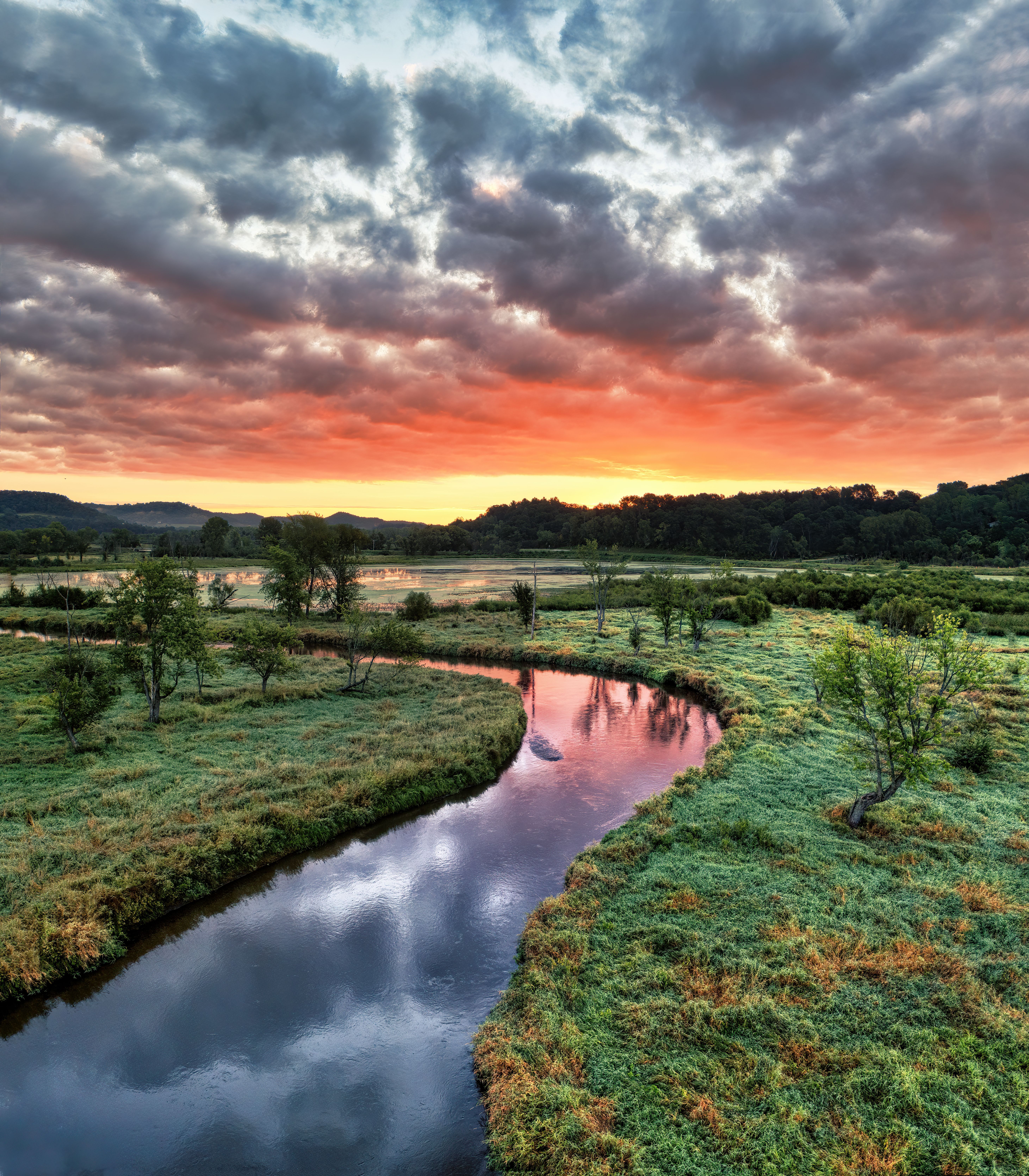 Green Grass Field Near River Under Cloudy Sky · Free Stock Photo