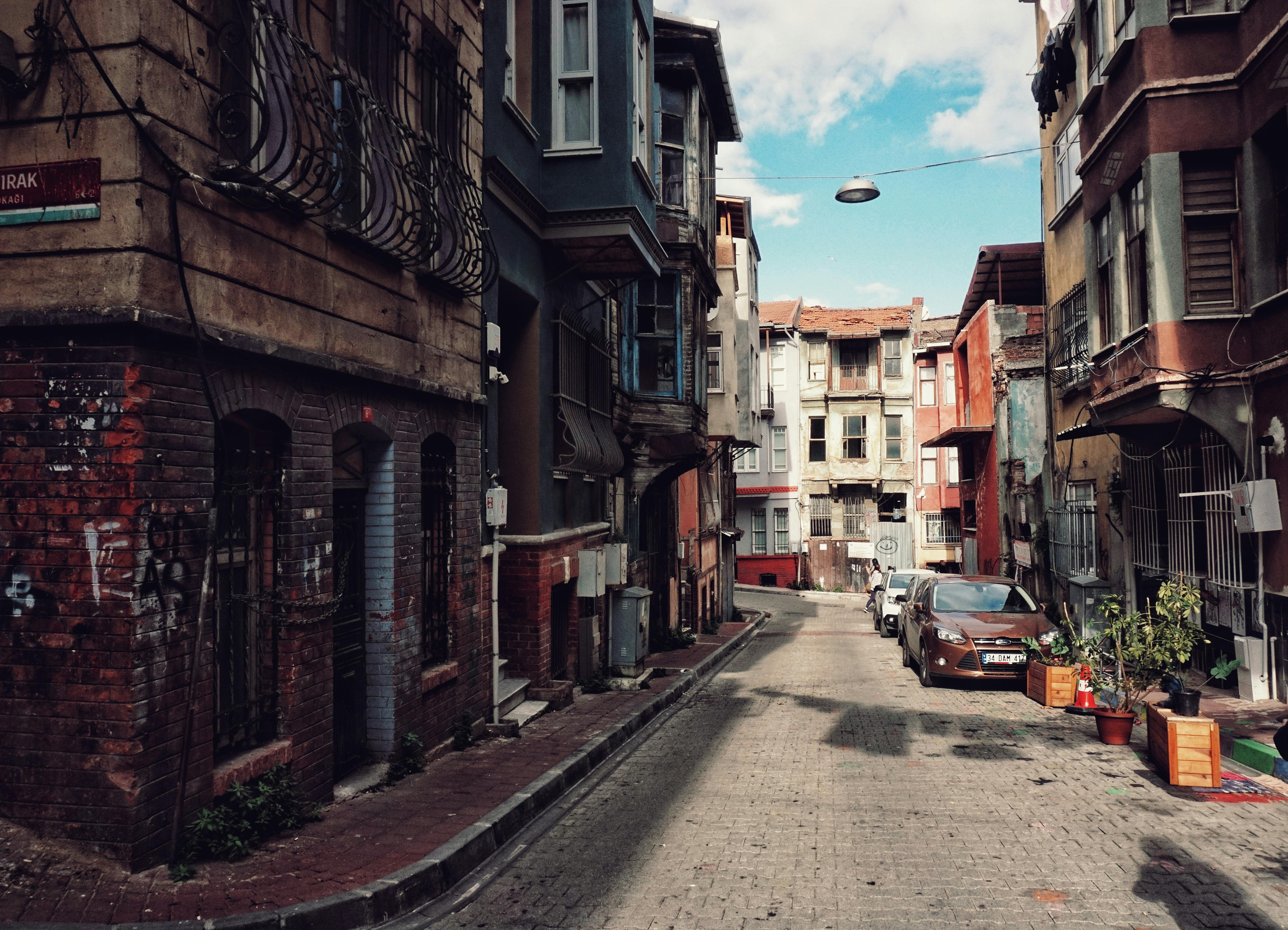 Cars Parked on Side of the Road in Between Buildings · Free Stock Photo