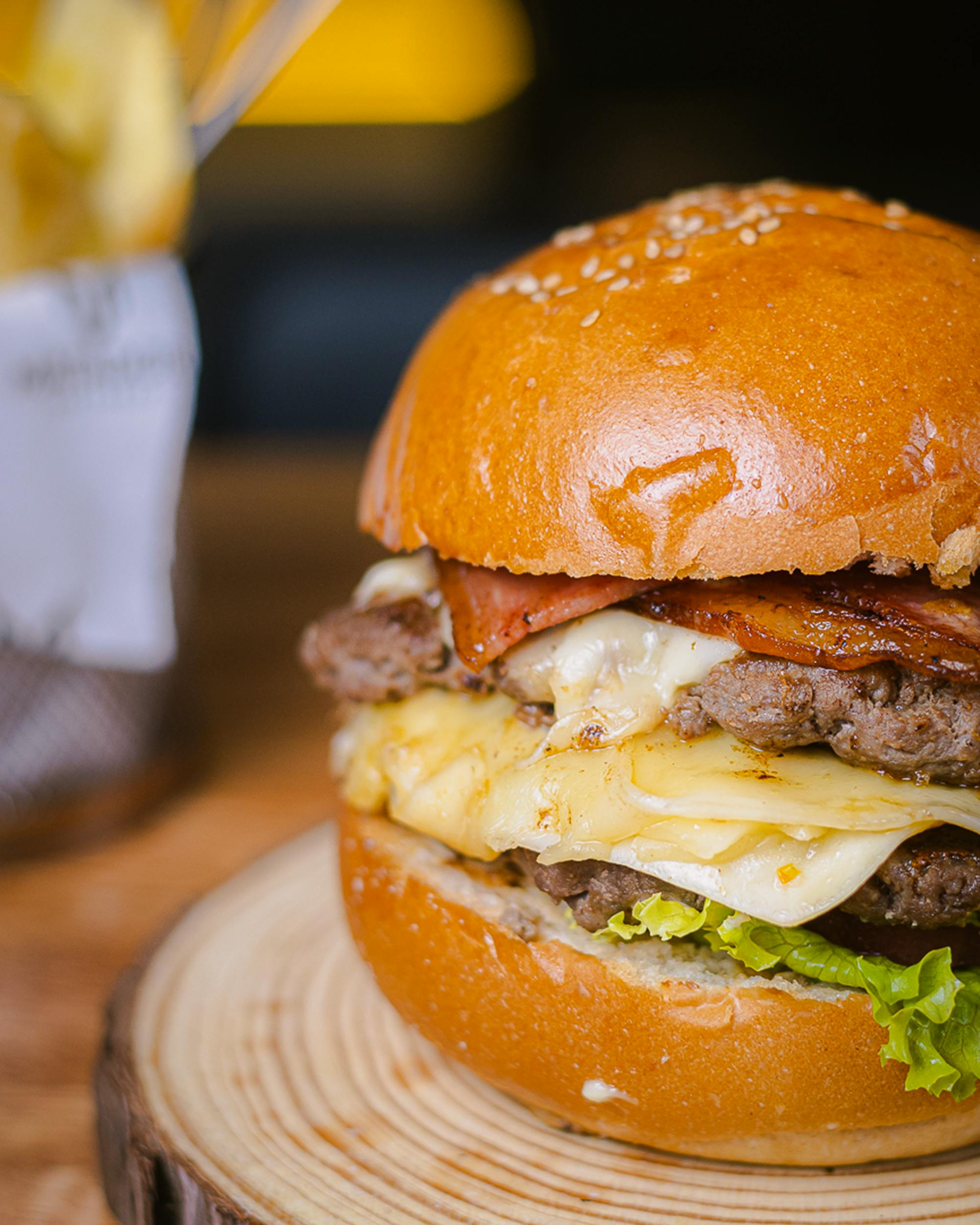 Hand Holding Cheesy Burger · Free Stock Photo