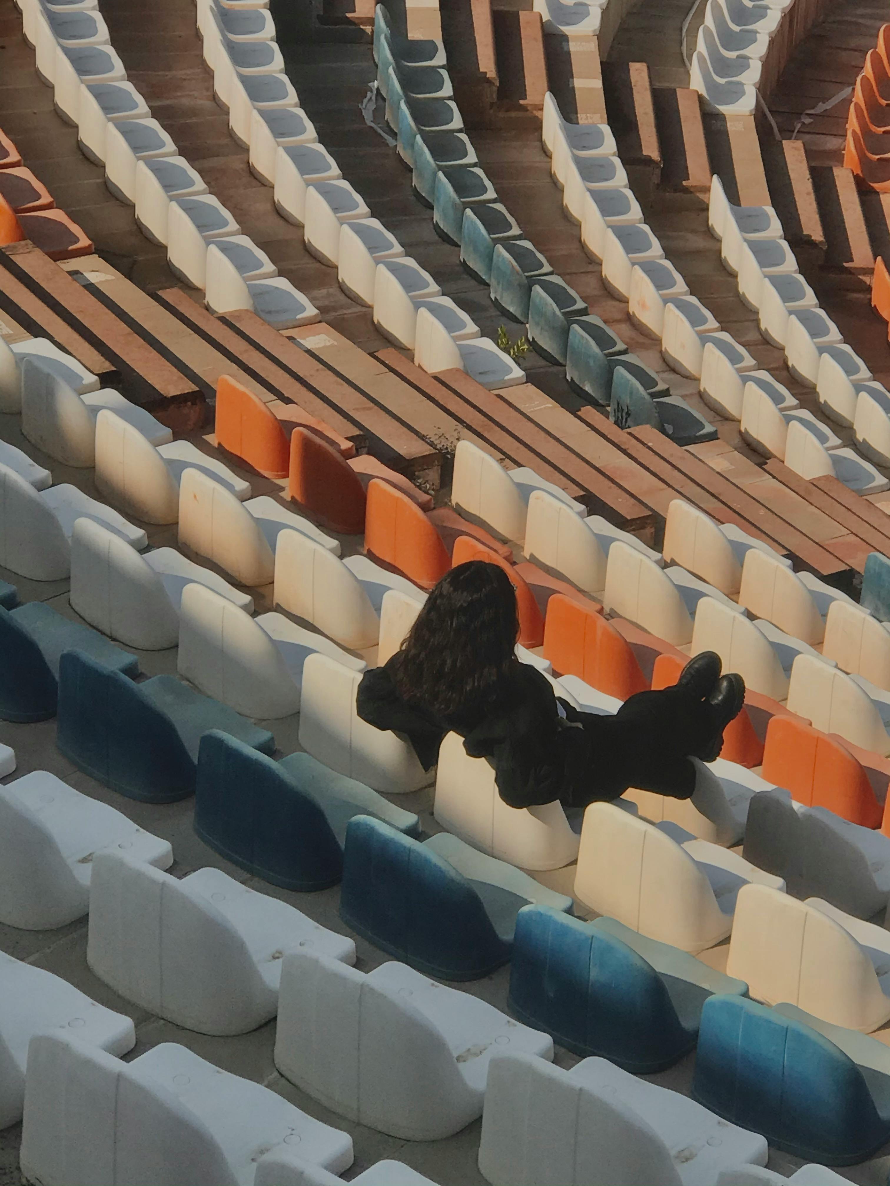 Man Sitting on Empty Stadium Auditorium · Free Stock Photo