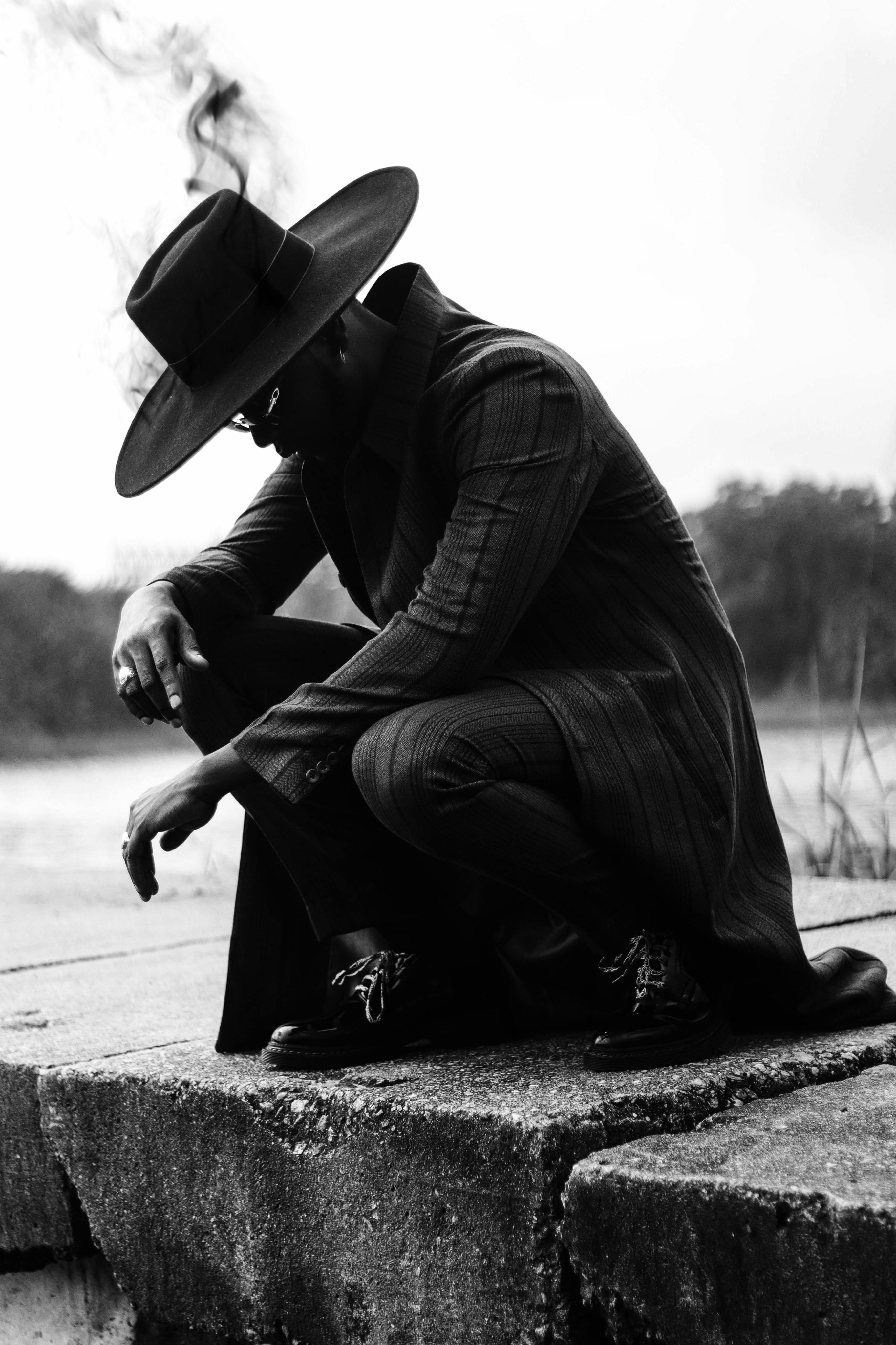 Man in Coat and Hat Crouching · Free Stock Photo