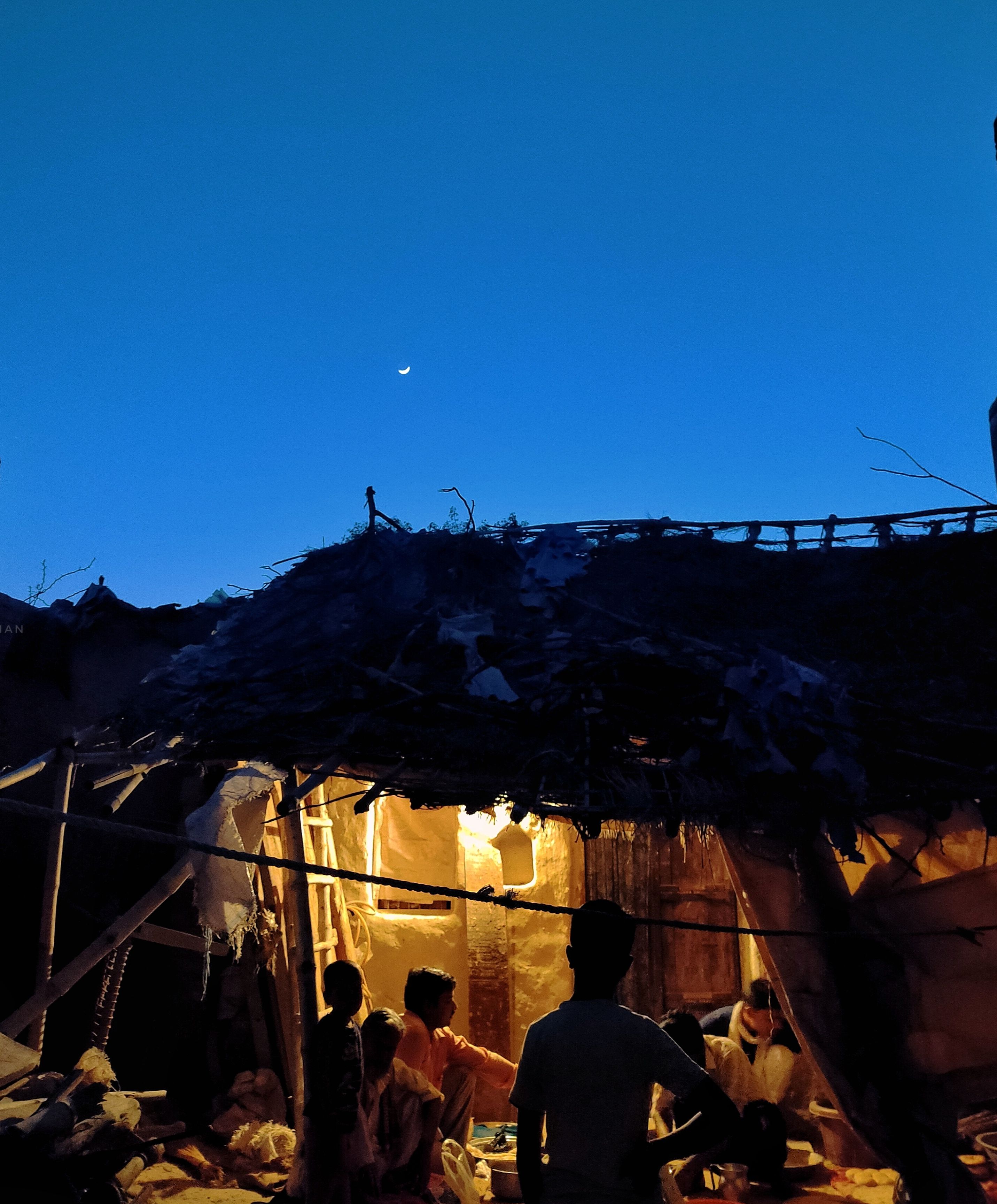 People Sitting Under a Thatched Roof at Night · Free Stock Photo
